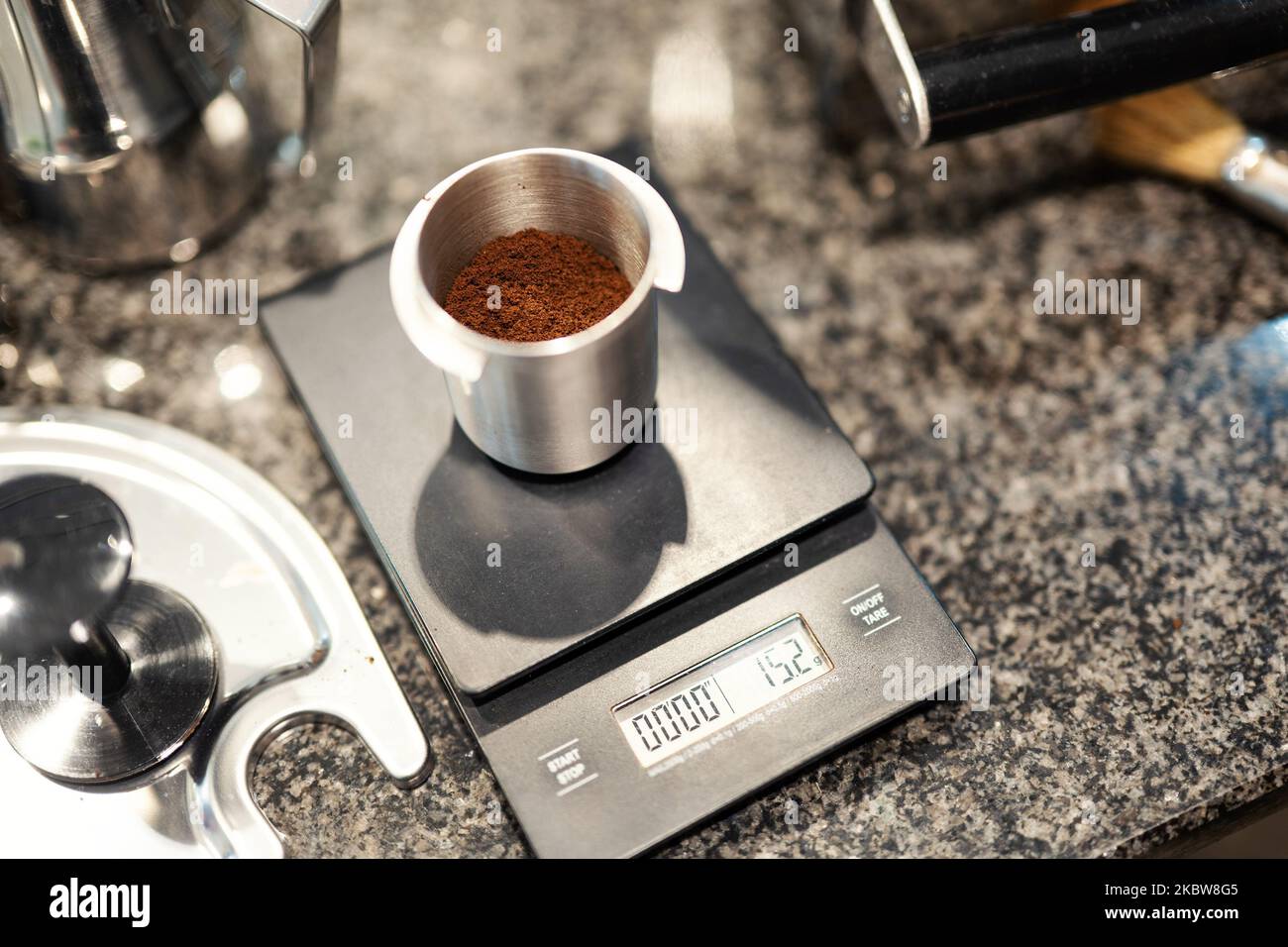 Freshly ground coffee is precisely weighed on a kitchen scale in an ...