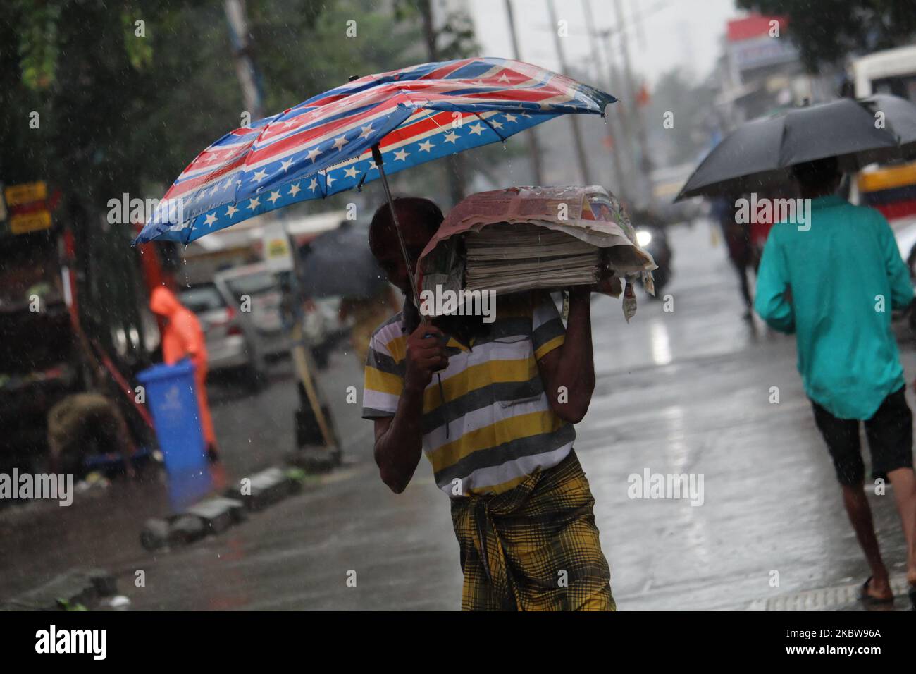 A street vendor sells newspapers during heavy rains in Mumbai, India on ...