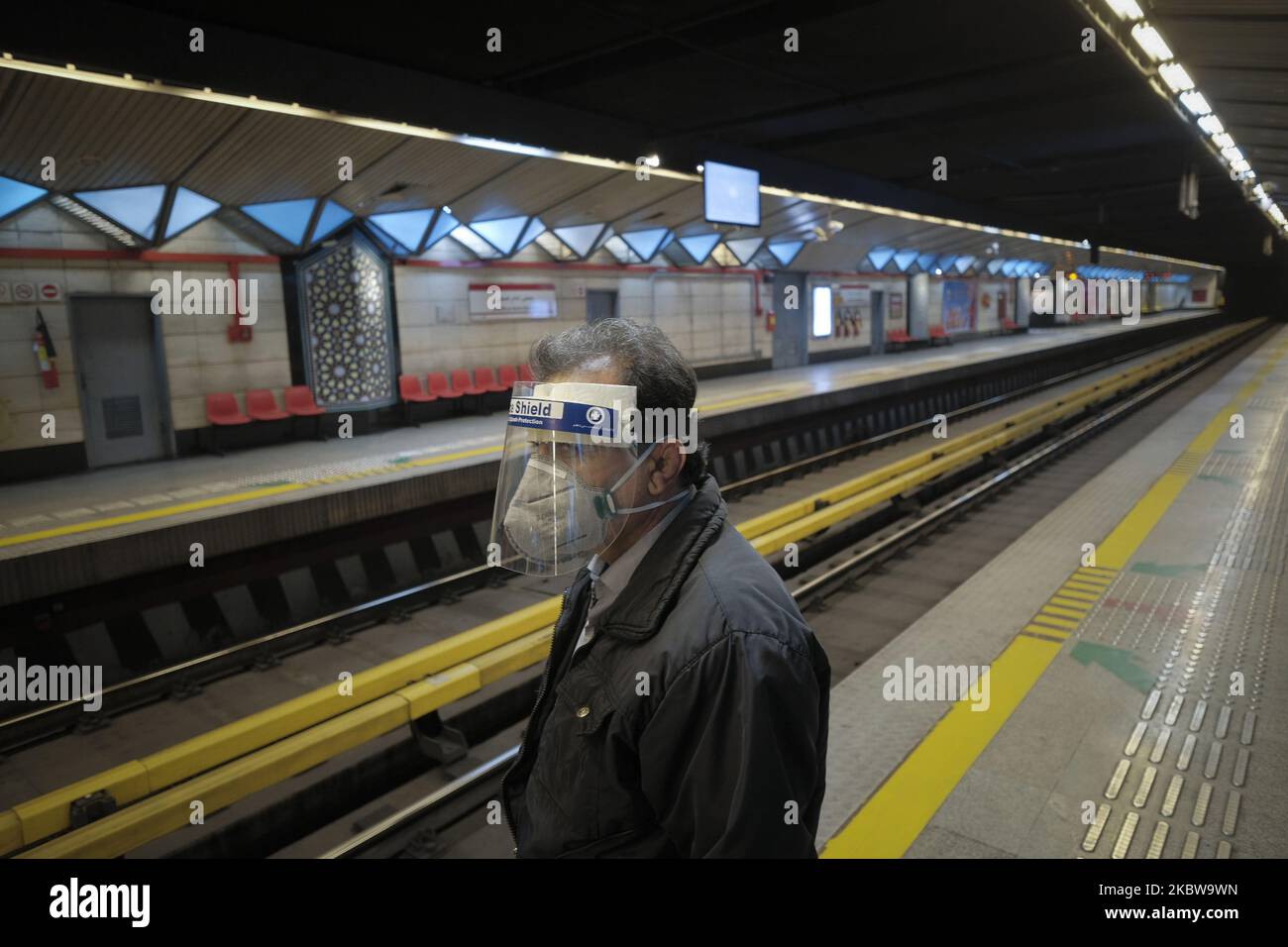 An Iranian man wearing a face mask and shield stands at an underground ...