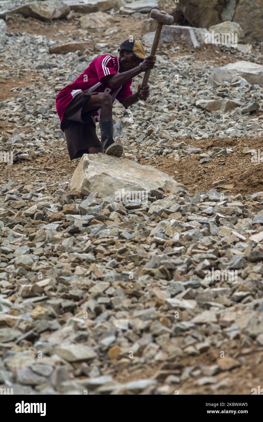 A traditional stone miner breaks stones in the hills in Lekatu Hamlet ...