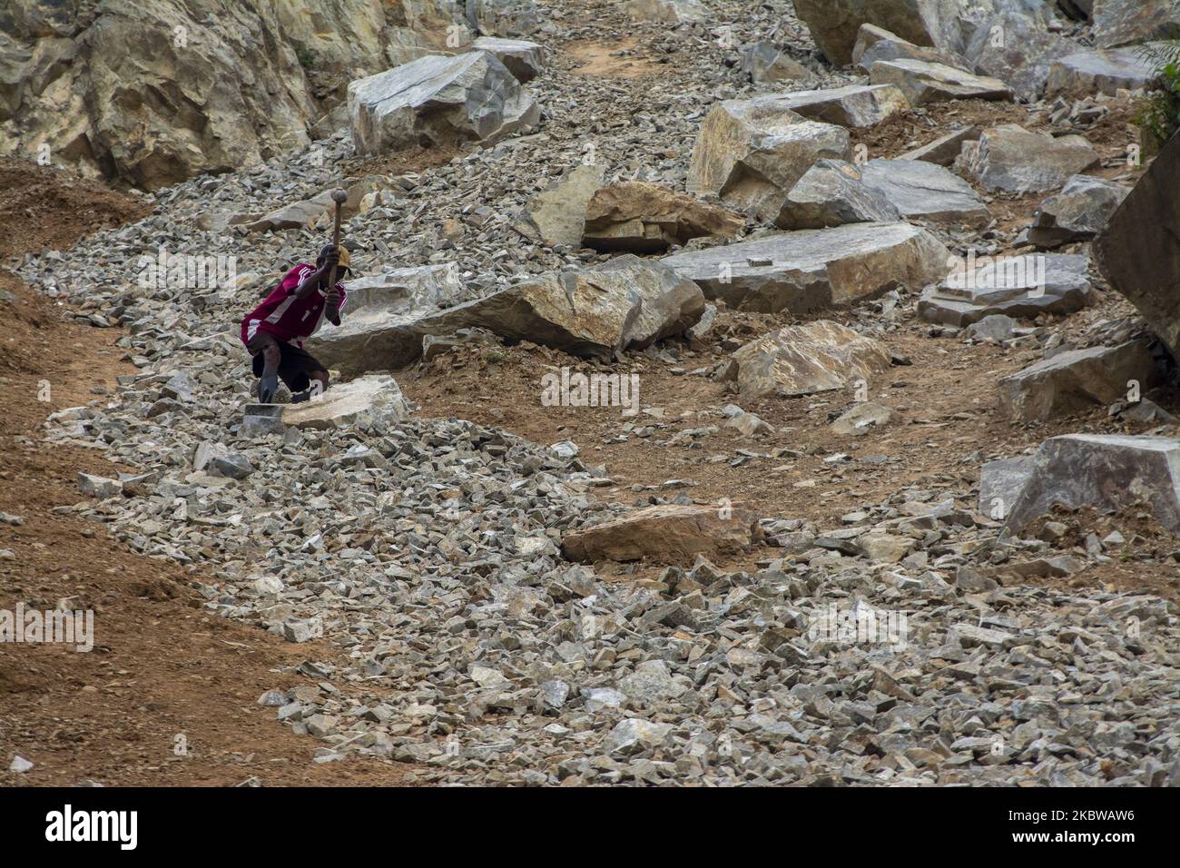 A traditional stone miner breaks stones in the hills in Lekatu Hamlet ...