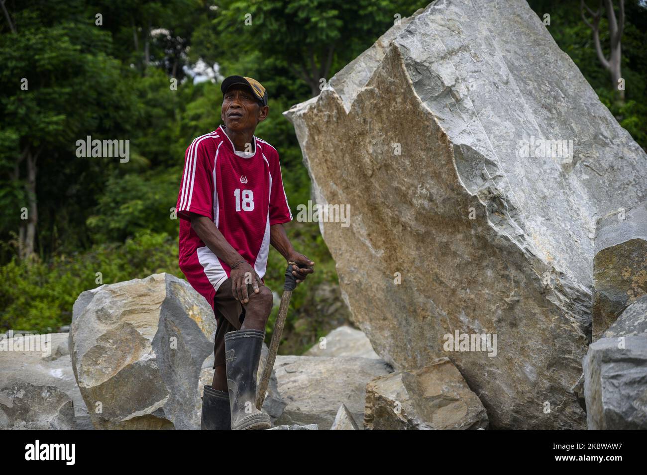 A traditional stone miner breaks stones in the hills in Lekatu Hamlet ...