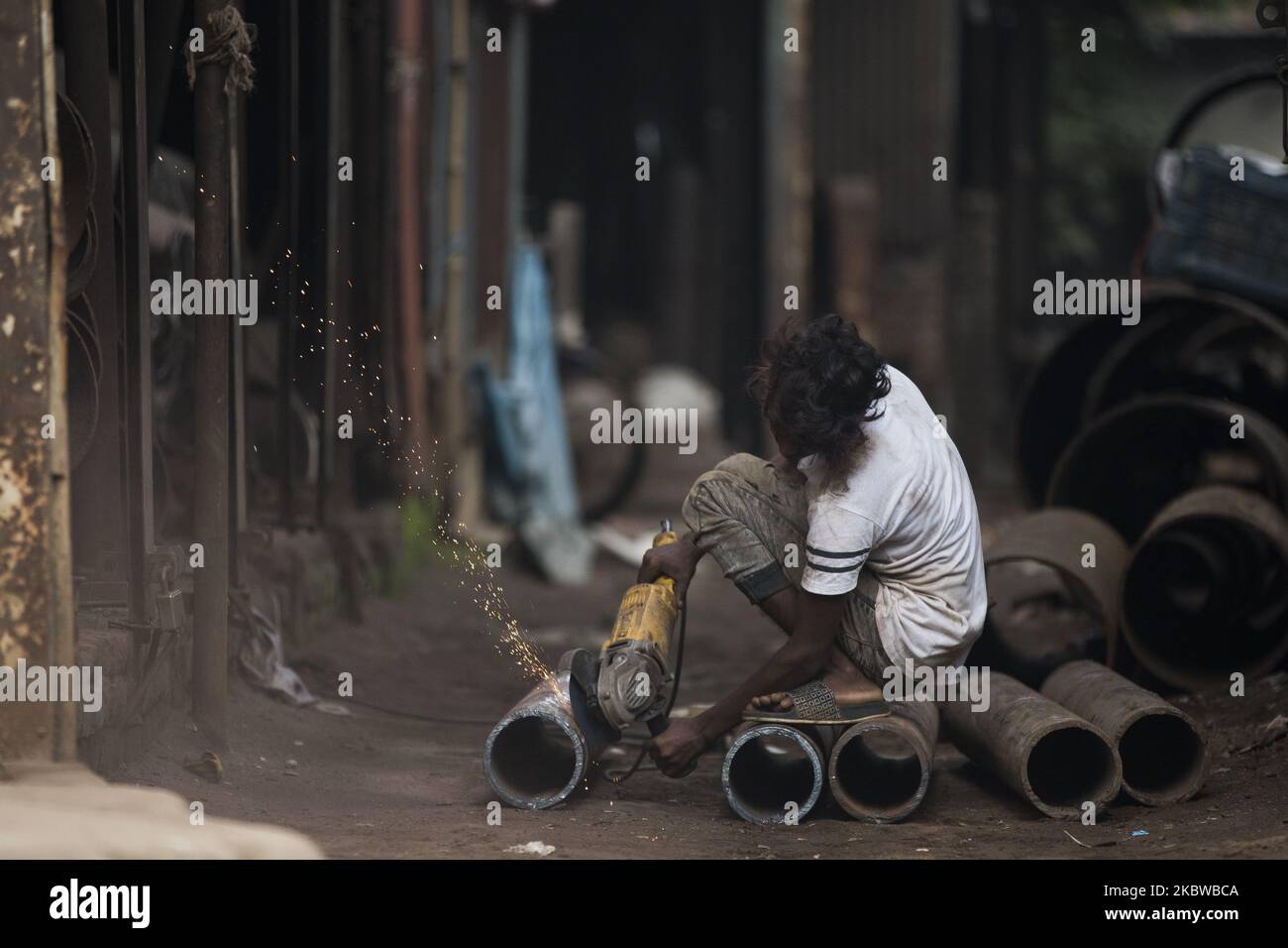 A youth welds a steel pipe at a workshop in Dhaka on July 27, 2020 ...