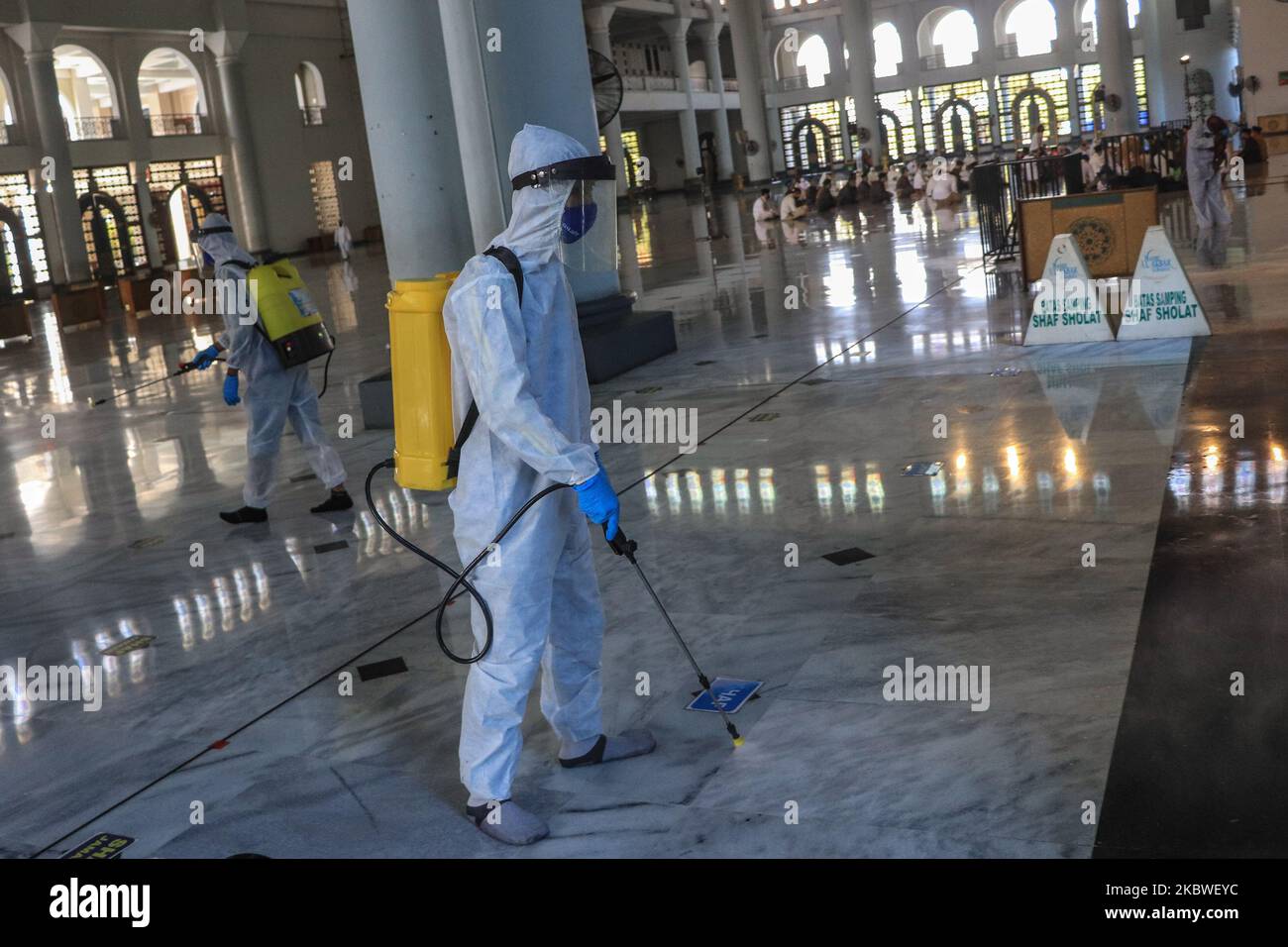Workers wearing personal protective equipment spray disinfectant liquid ...