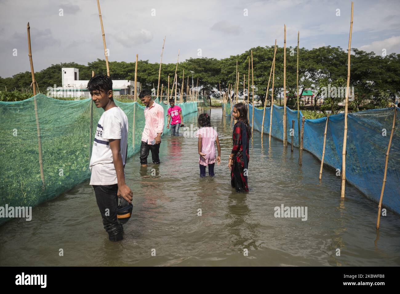People make their way through flood water on the outskirts of Dhaka on ...
