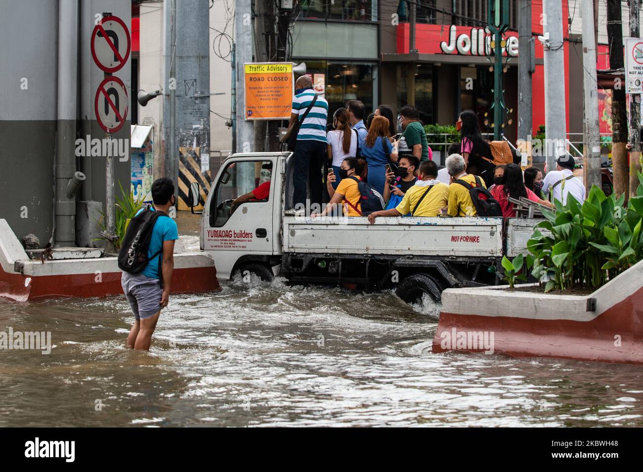 A mini truck carrying passengers wades through flood water caused by a ...