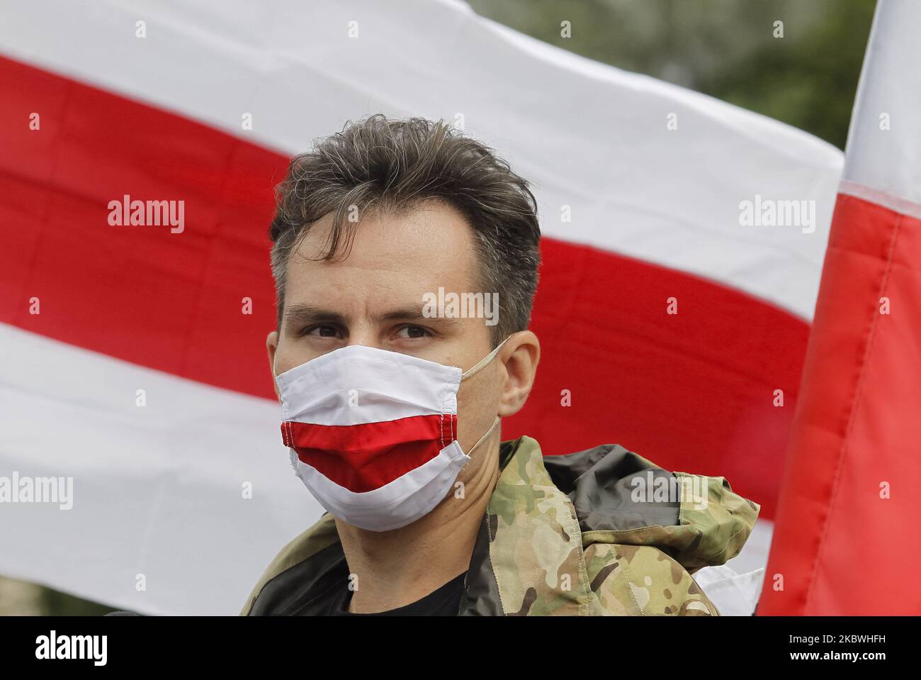 A man wearing a face mask in colors of Belarusian flag attends a rally ...