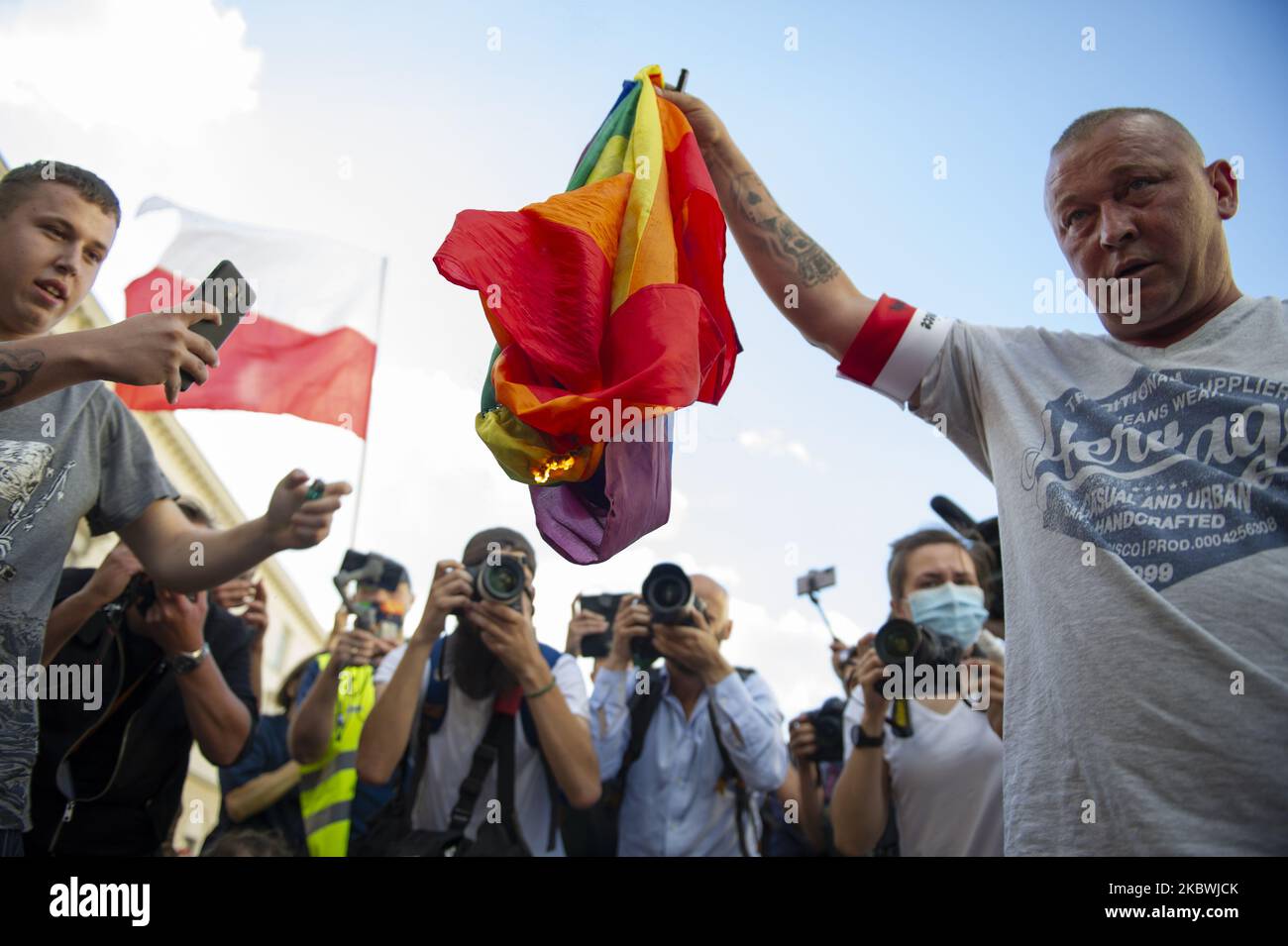 A demonstrator holds a burning rainbow flag during the 76th Warsaw ...