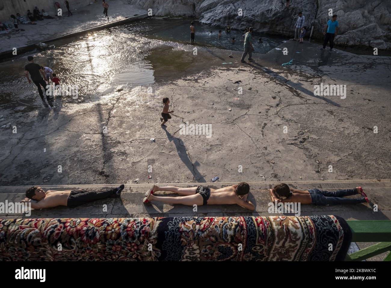 Iranian boys lie on the ground to dry themselves after swimming in the ...