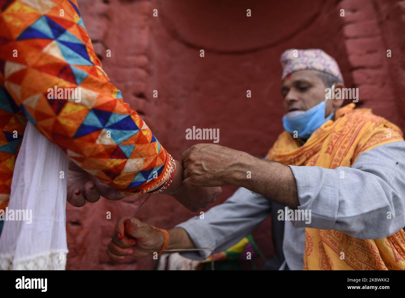 A Priest tied “Doro” a sacred colorful thread around their wrest of a ...