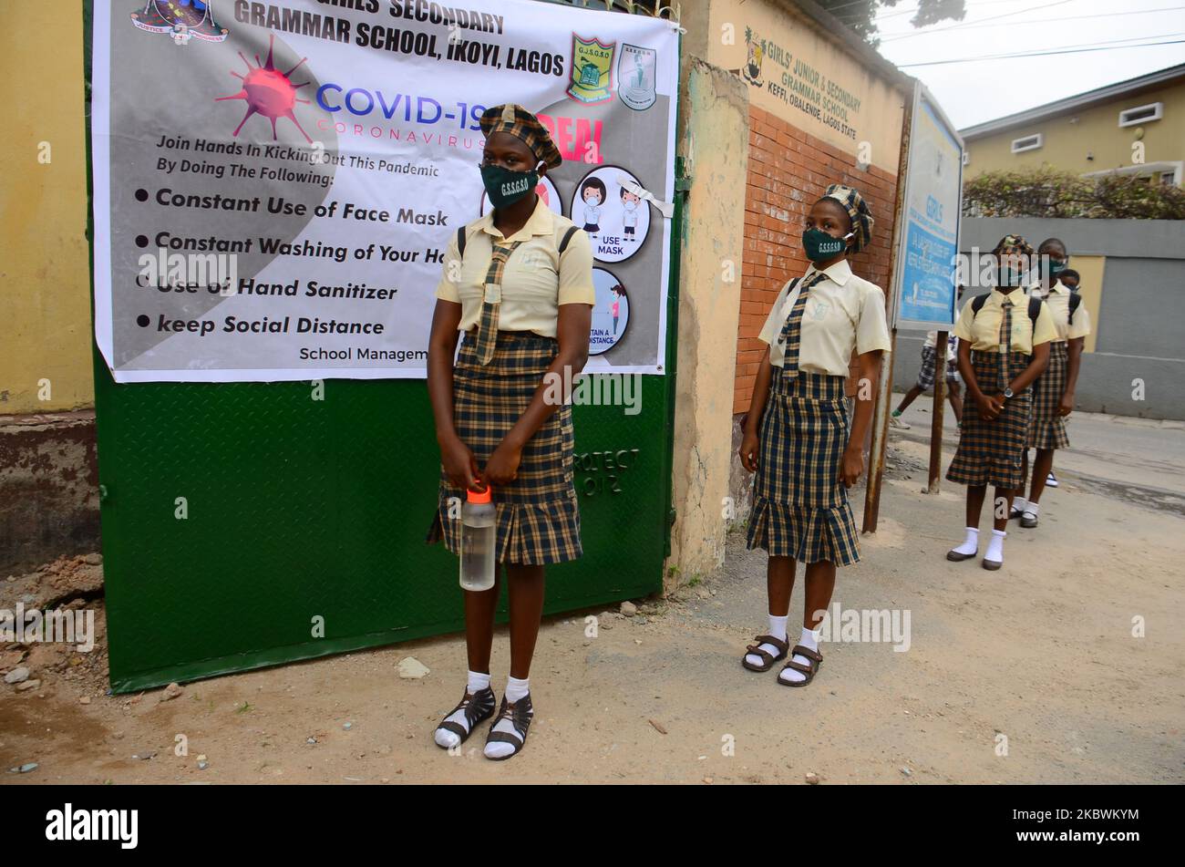 High school students wear face masks as they wait outside the entrance ...