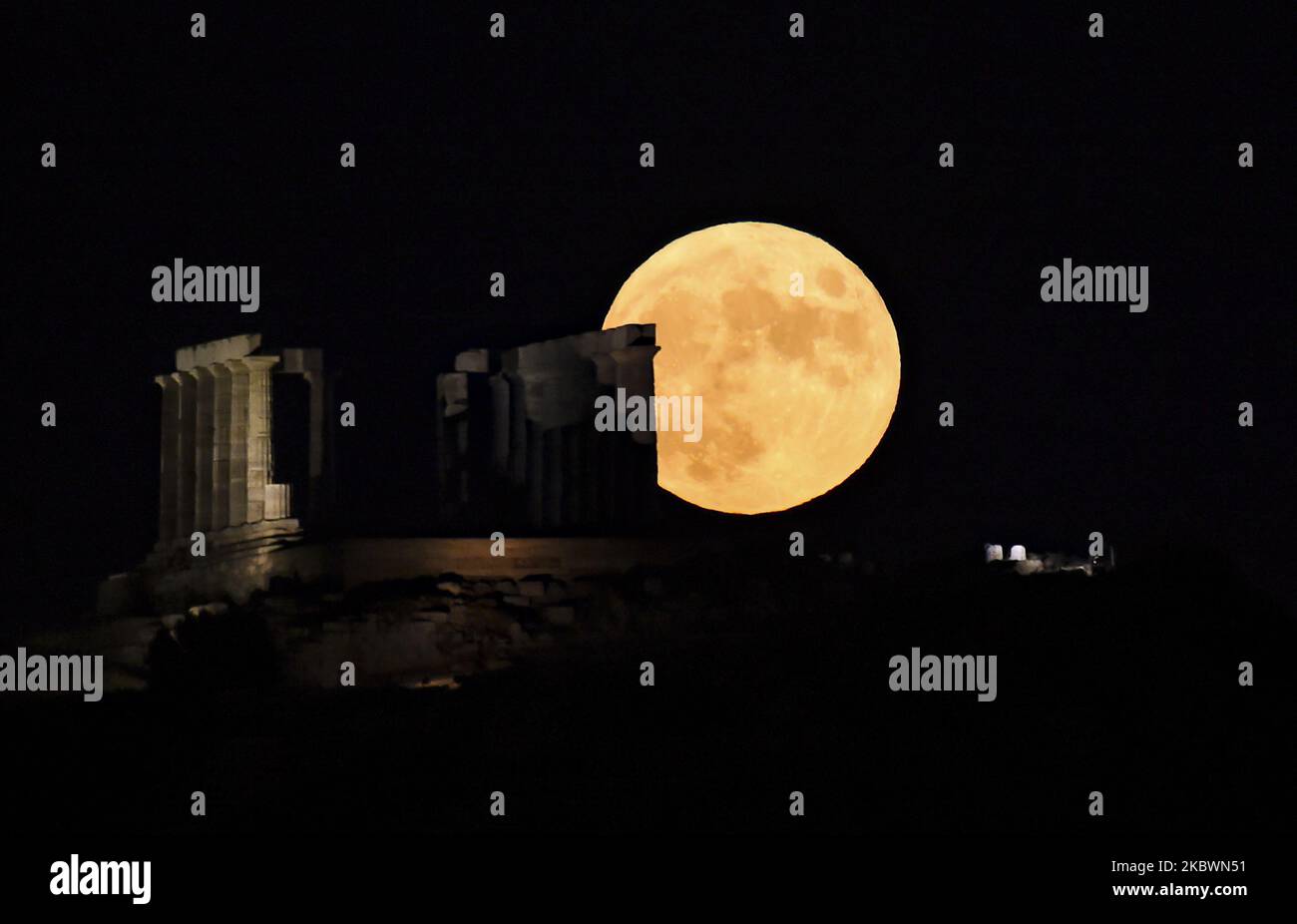 The full moon rises next to the Poseidon Temple at the Cape of Sounion ...