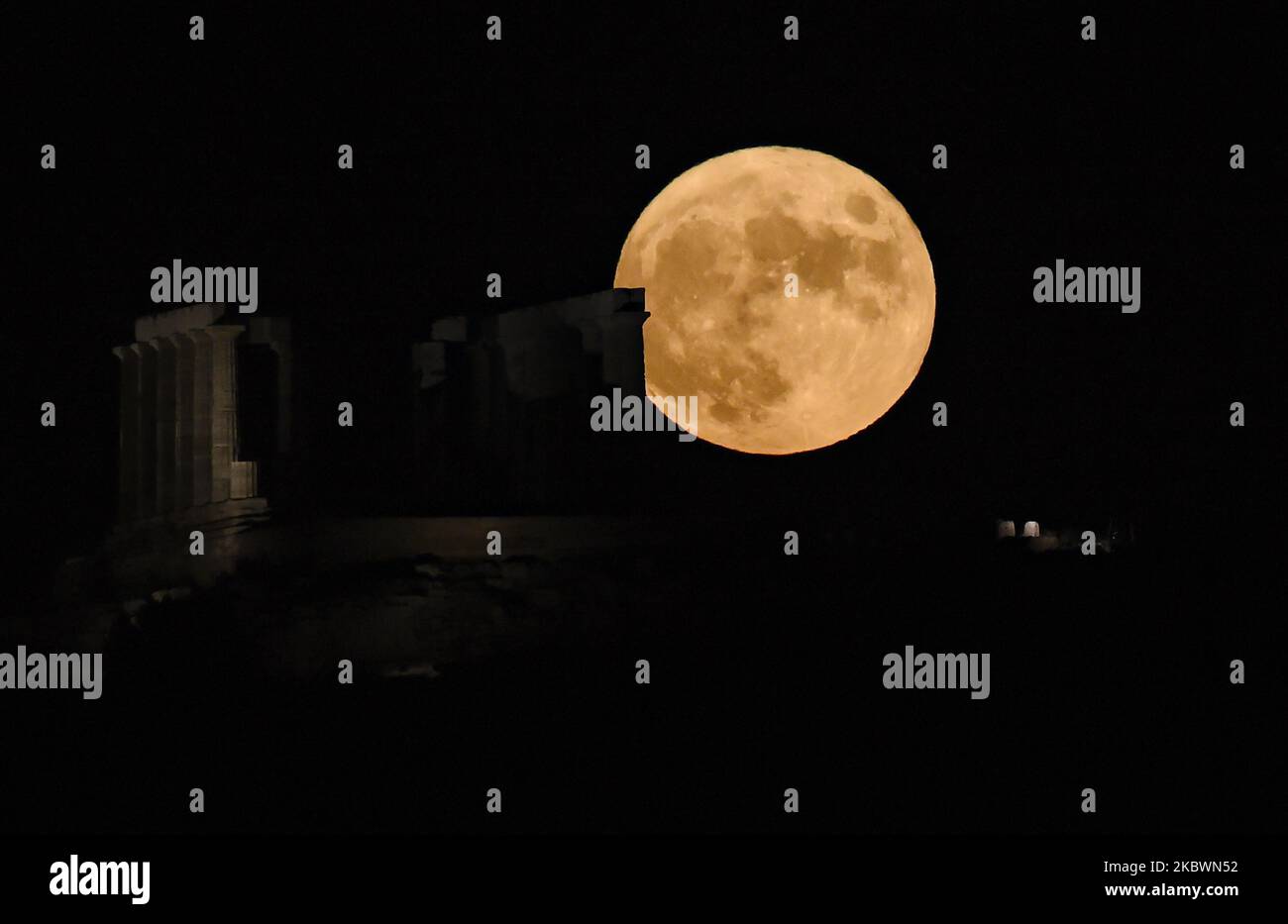 The full moon rises next to the Poseidon Temple at the Cape of Sounion ...
