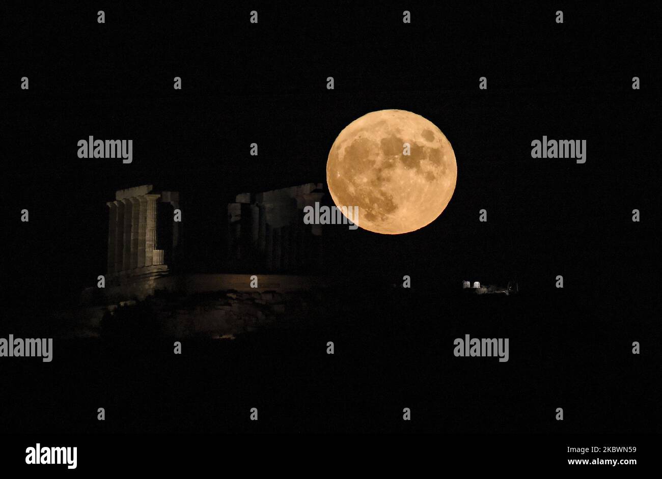 The full moon rises next to the Poseidon Temple at the Cape of Sounion ...