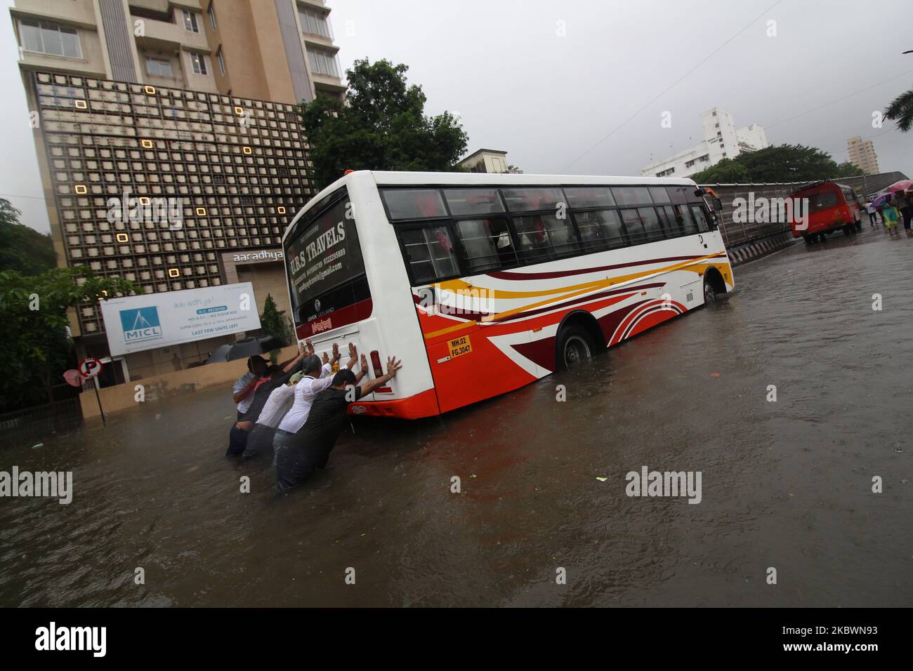 People push a bus through a flooded road during heavy rains in Mumbai ...