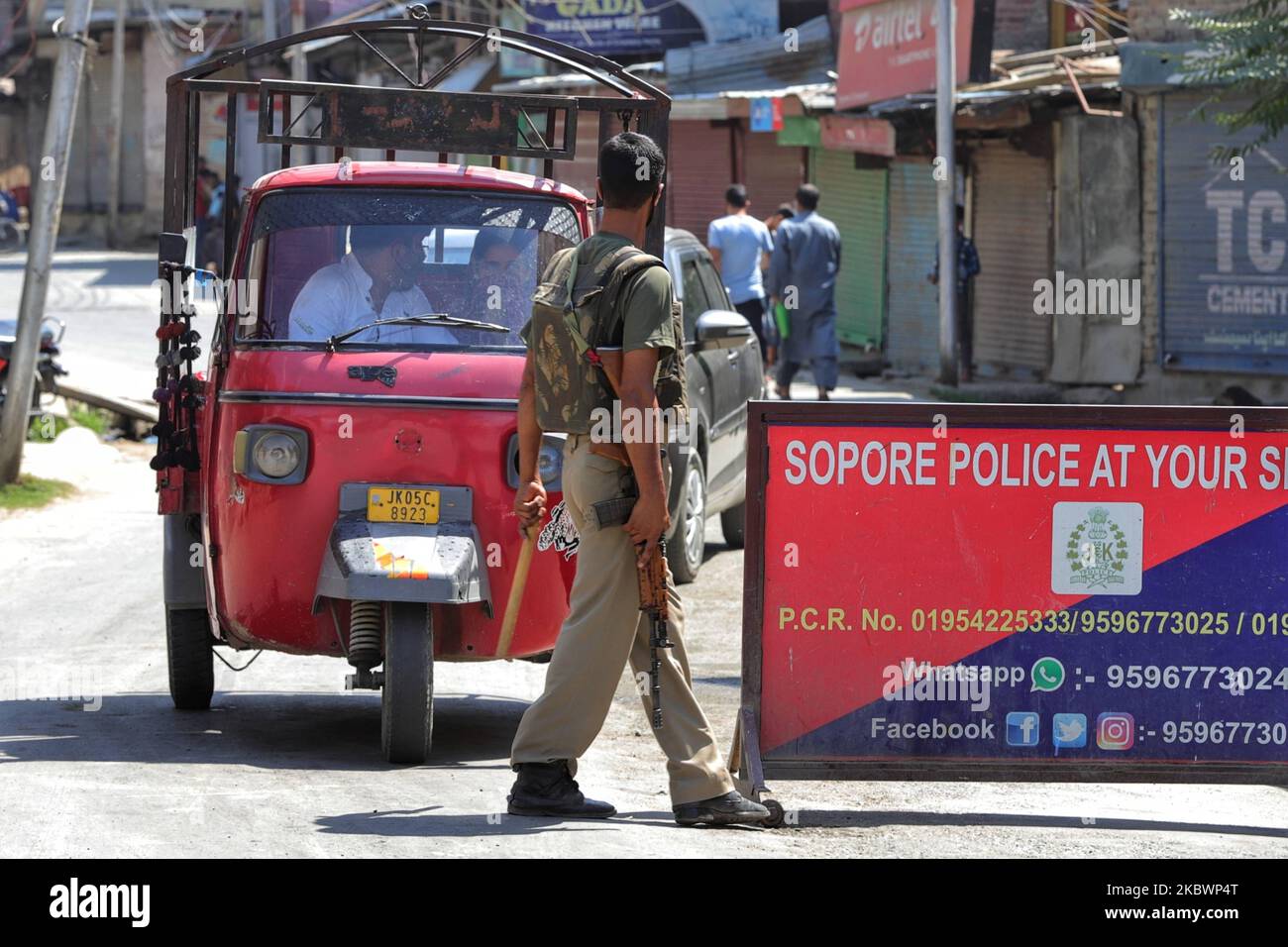 A police Cop stops an Auto Rickshaw in Sopore Town of District ...