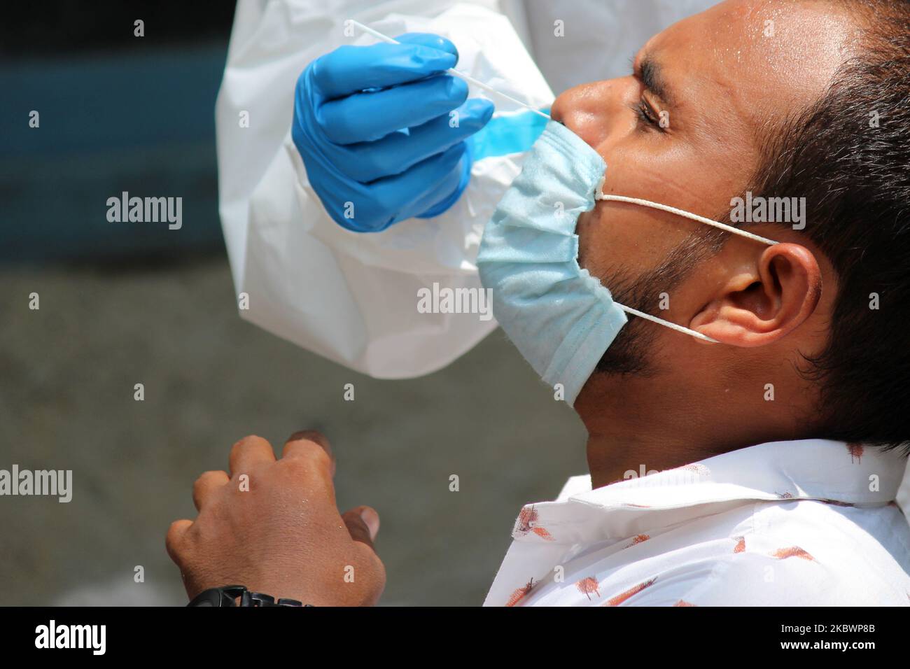 A health worker in personal protective equipment (PPE) collects a swab ...