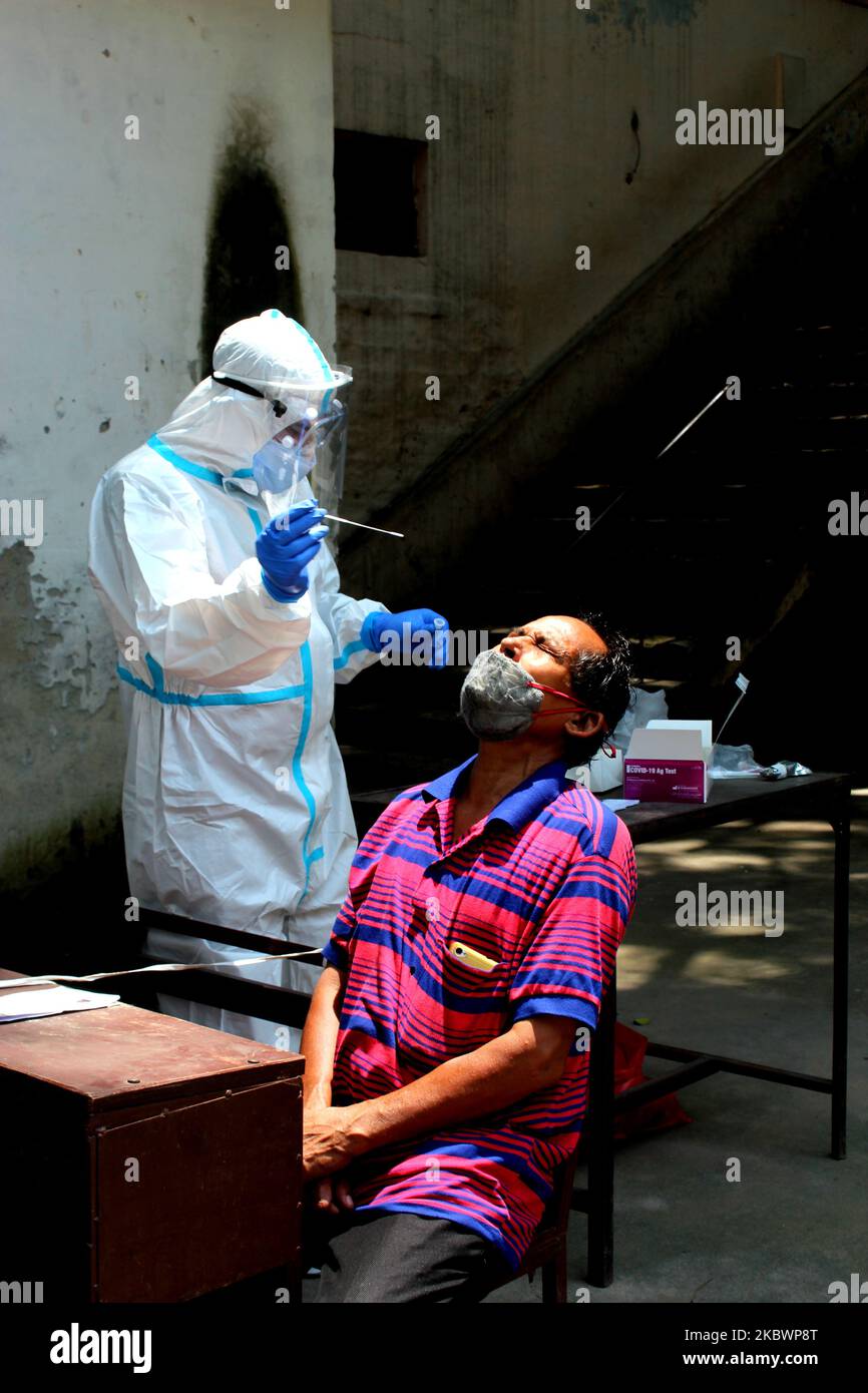 A health worker in personal protective equipment (PPE) collects a swab ...