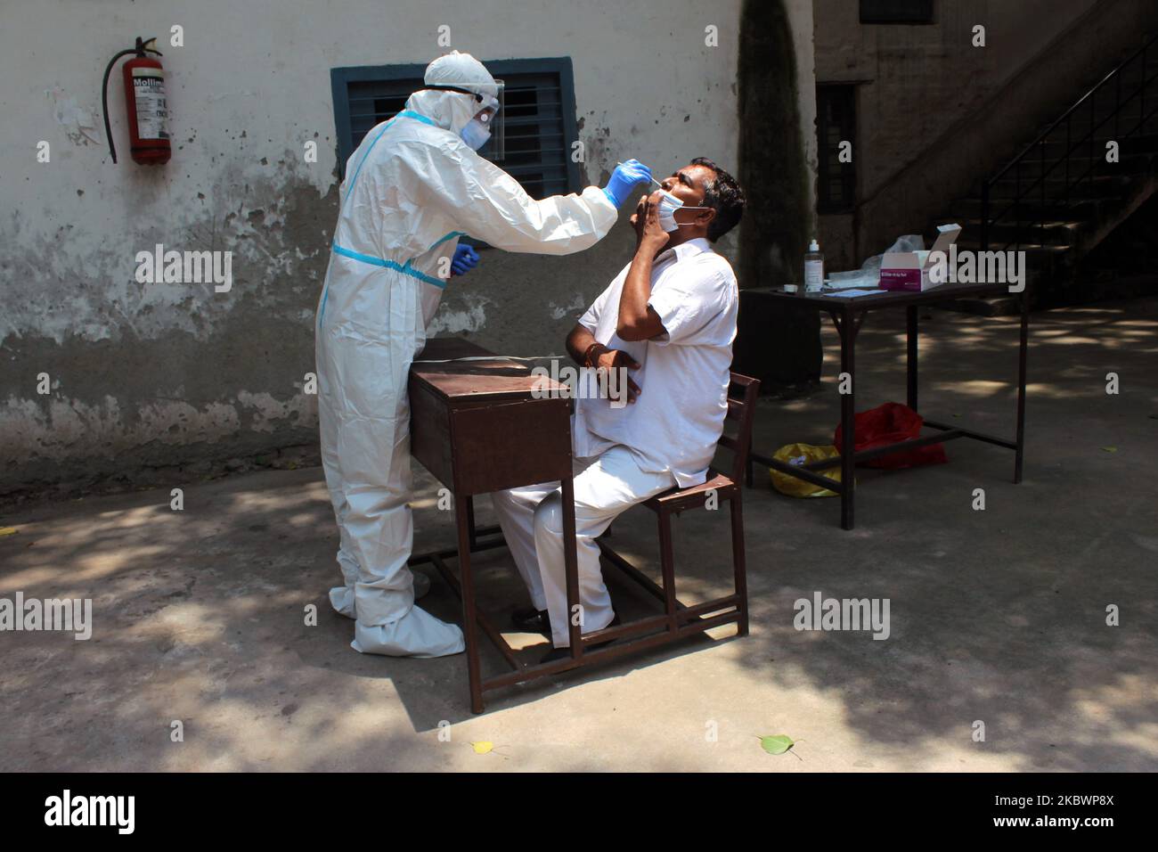 A health worker in personal protective equipment (PPE) collects a swab ...