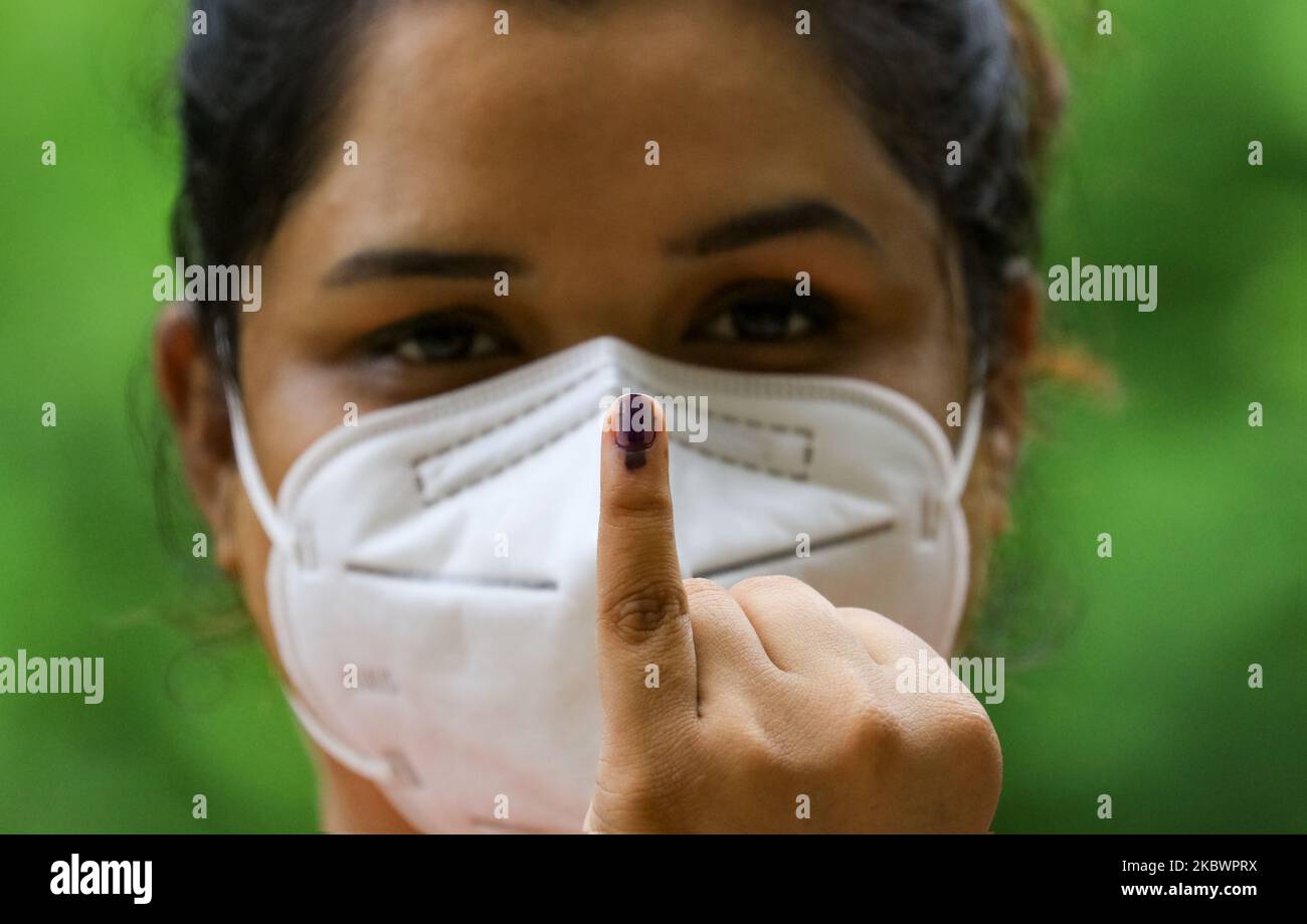 A Sri Lankan voter wearing a face mask shows the indelible ink mark on ...