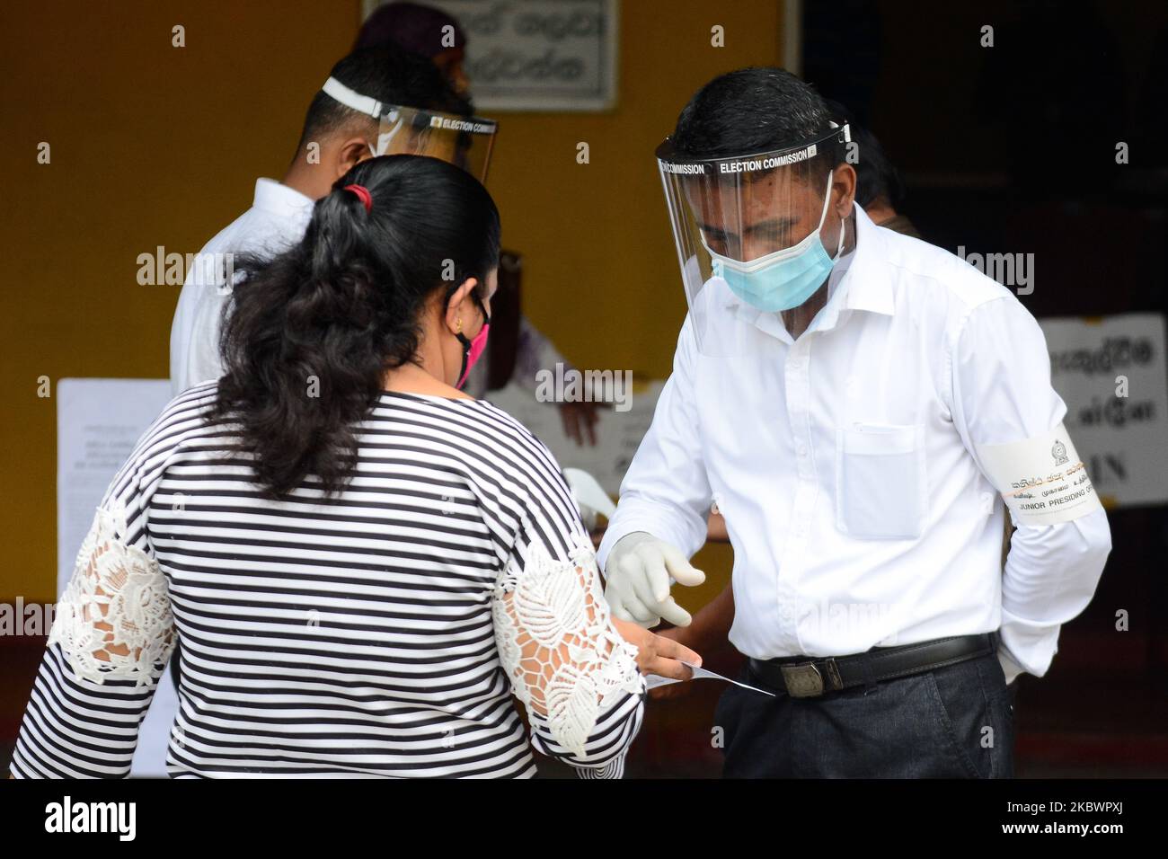 An official wearing a face shield check his details before casting her ...