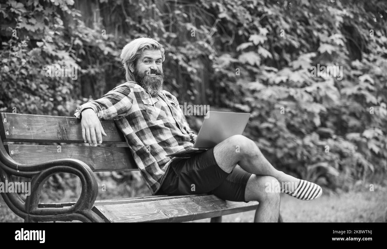 Really busy. mature man sitting on park bench with laptop and checking ...