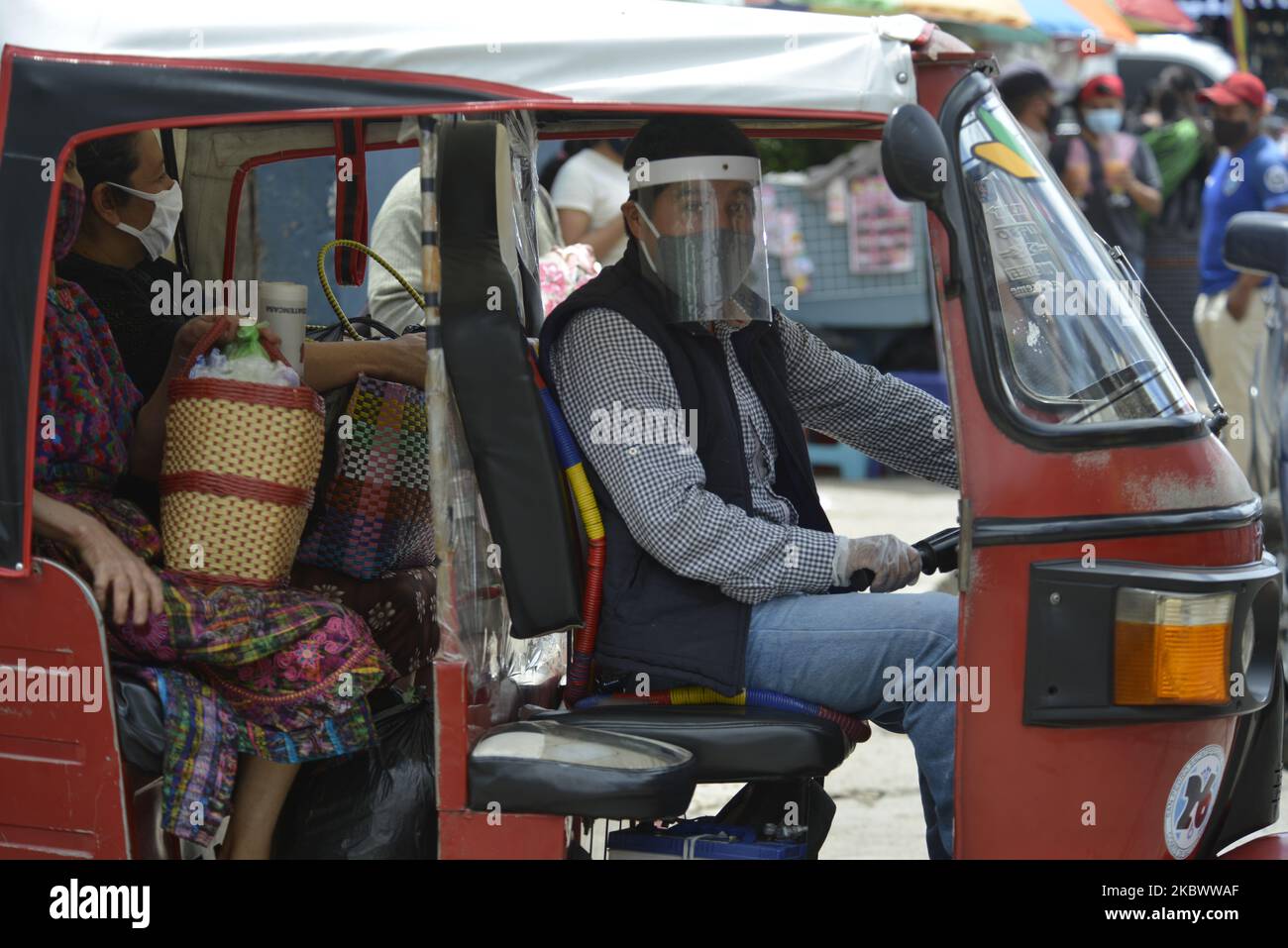 A tuc-tuc taxi driver transports Guatemalans on the streets of San ...