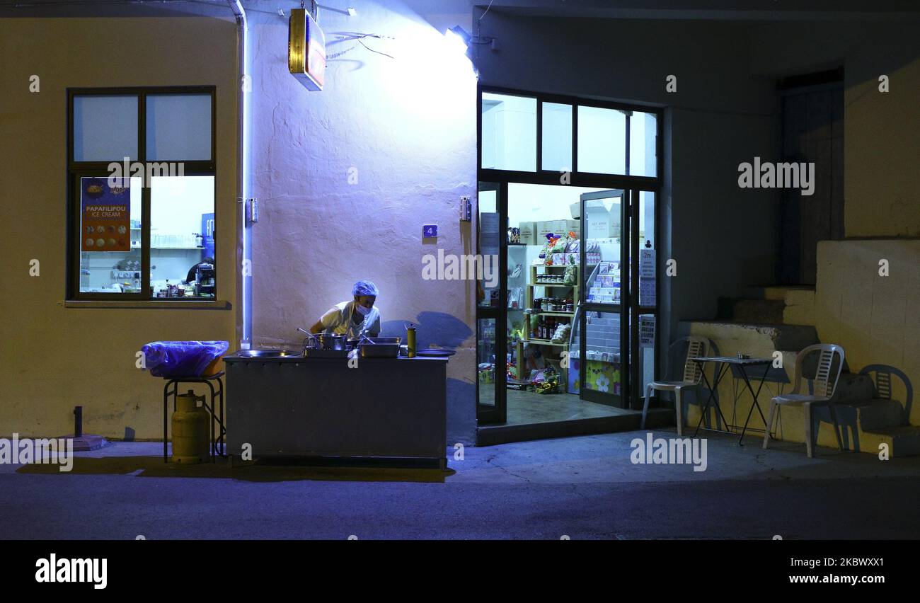 An elderly woman wearing a mask cooks traditional Cypriot sweets ...