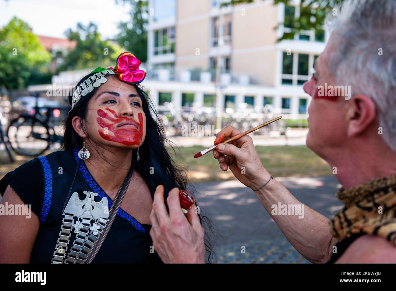 A man is painting a red hand on the face of an indigenous woman before ...