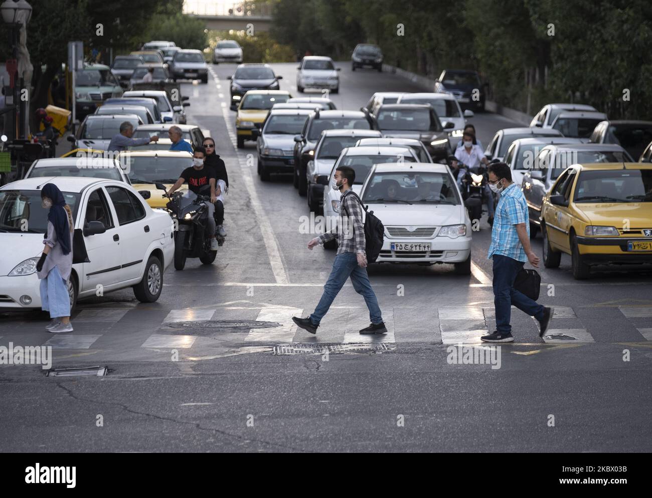 Iranian men wearing protective face masks cross an avenue in northern ...