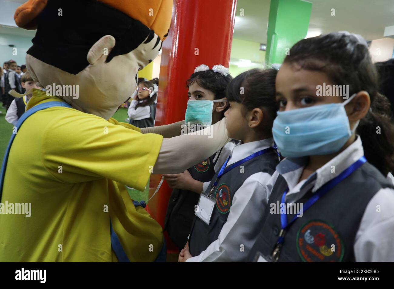 A clown hired by a local kindergarten instructs children how to wear a ...