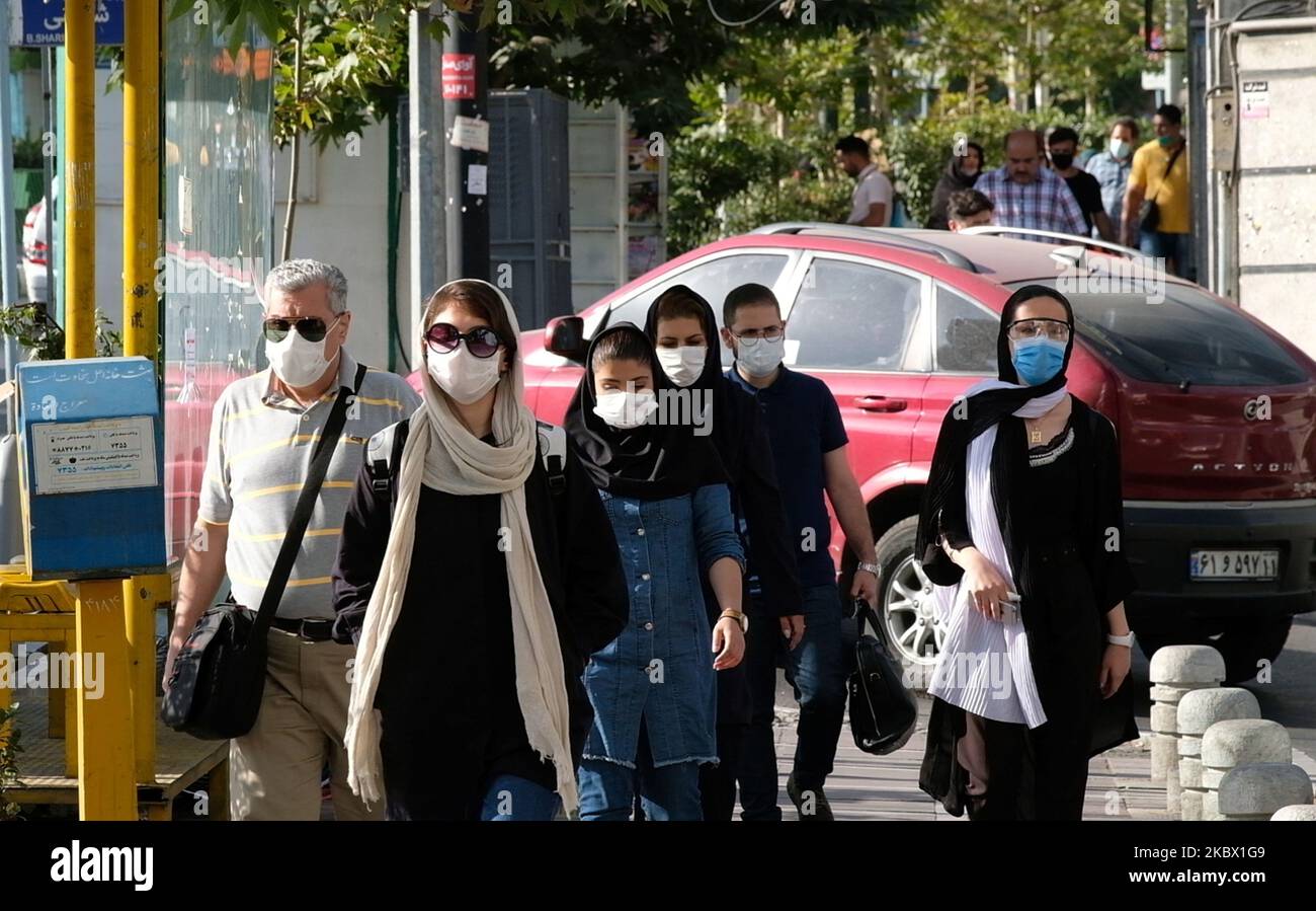 Iranian people wearing protective face masks walk along an avenue in ...