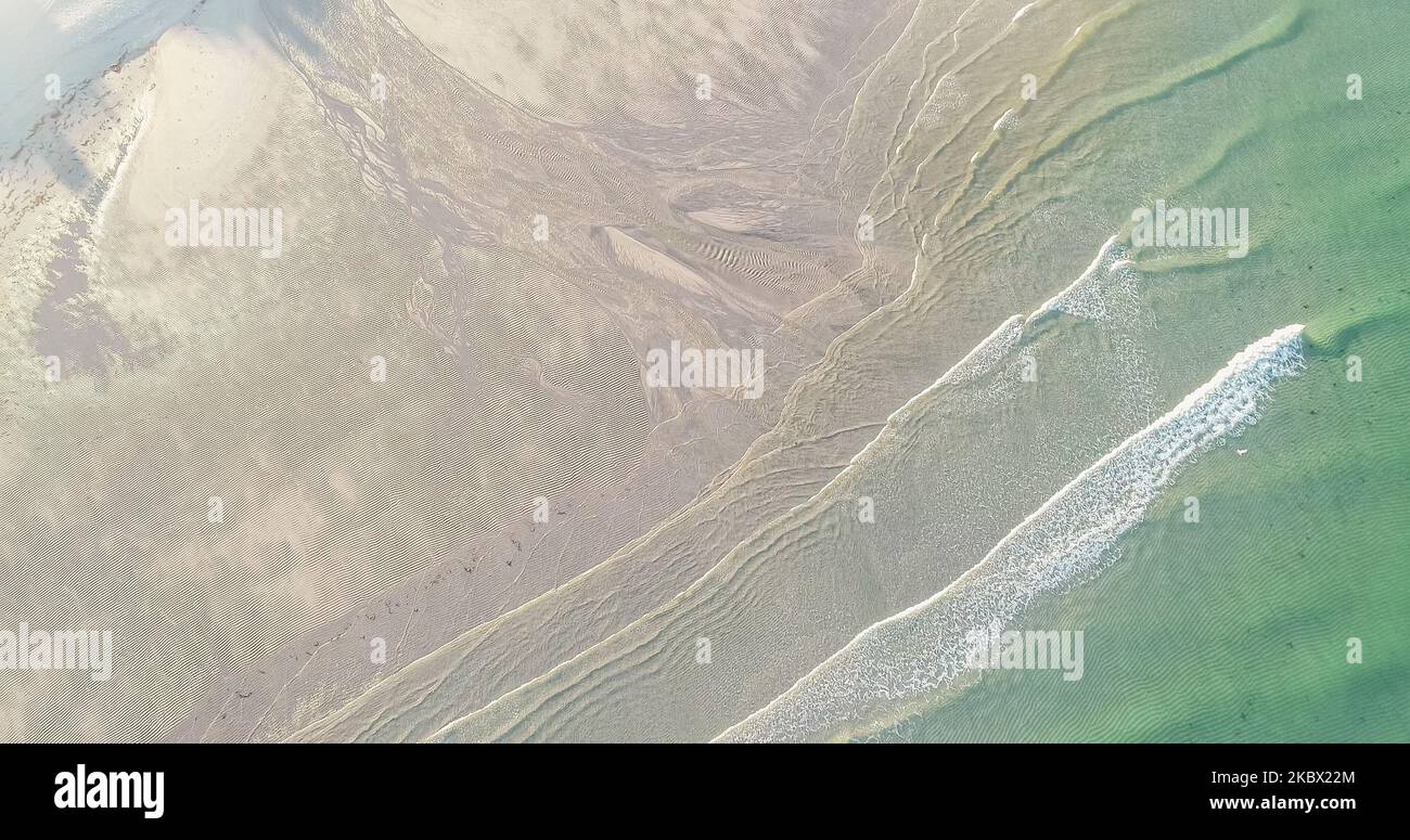 An aerial view of calm ocean waves on the beach at sunrise Stock Photo ...