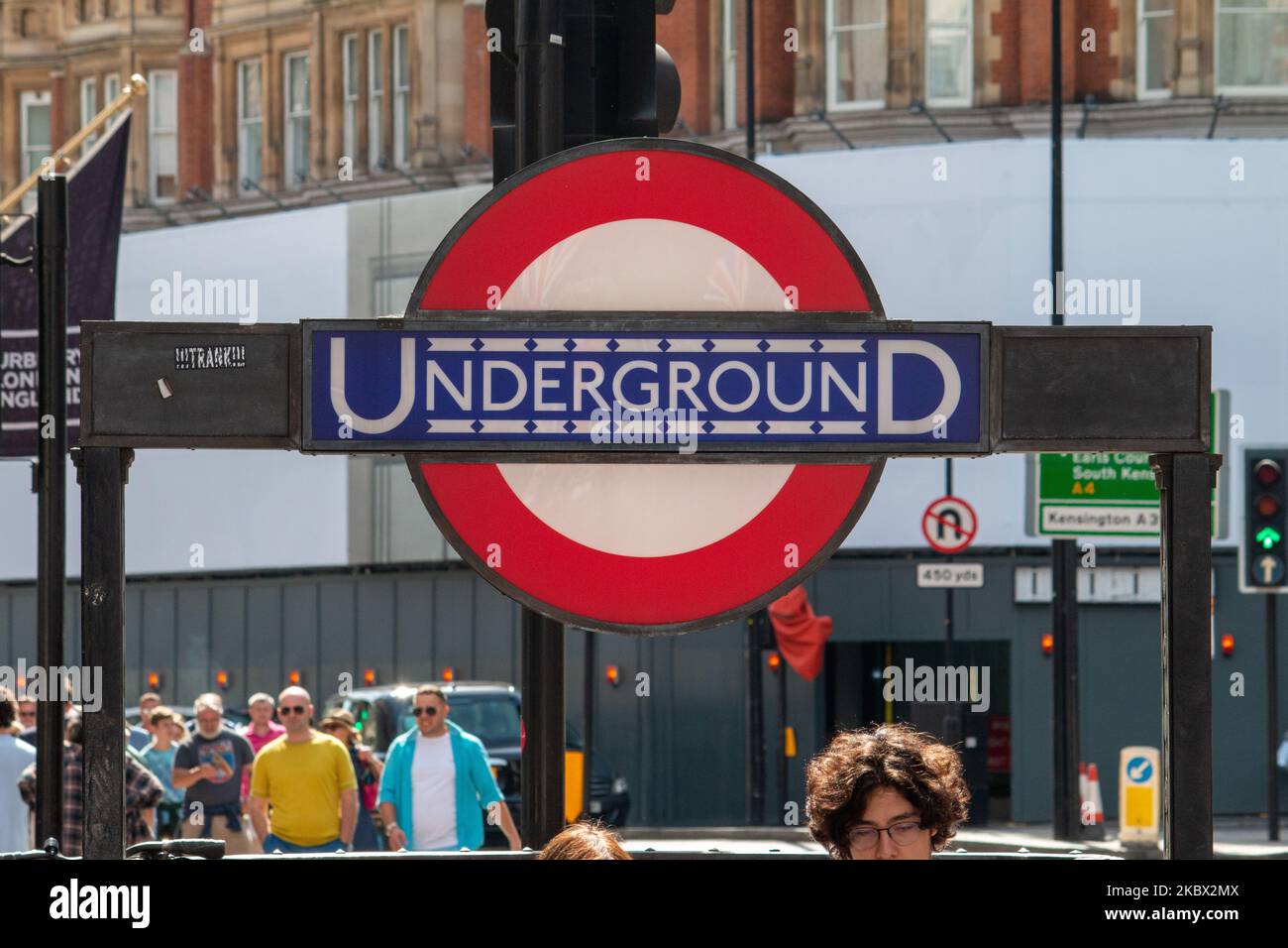 A group of people walking by a red circle sign leading to London's ...
