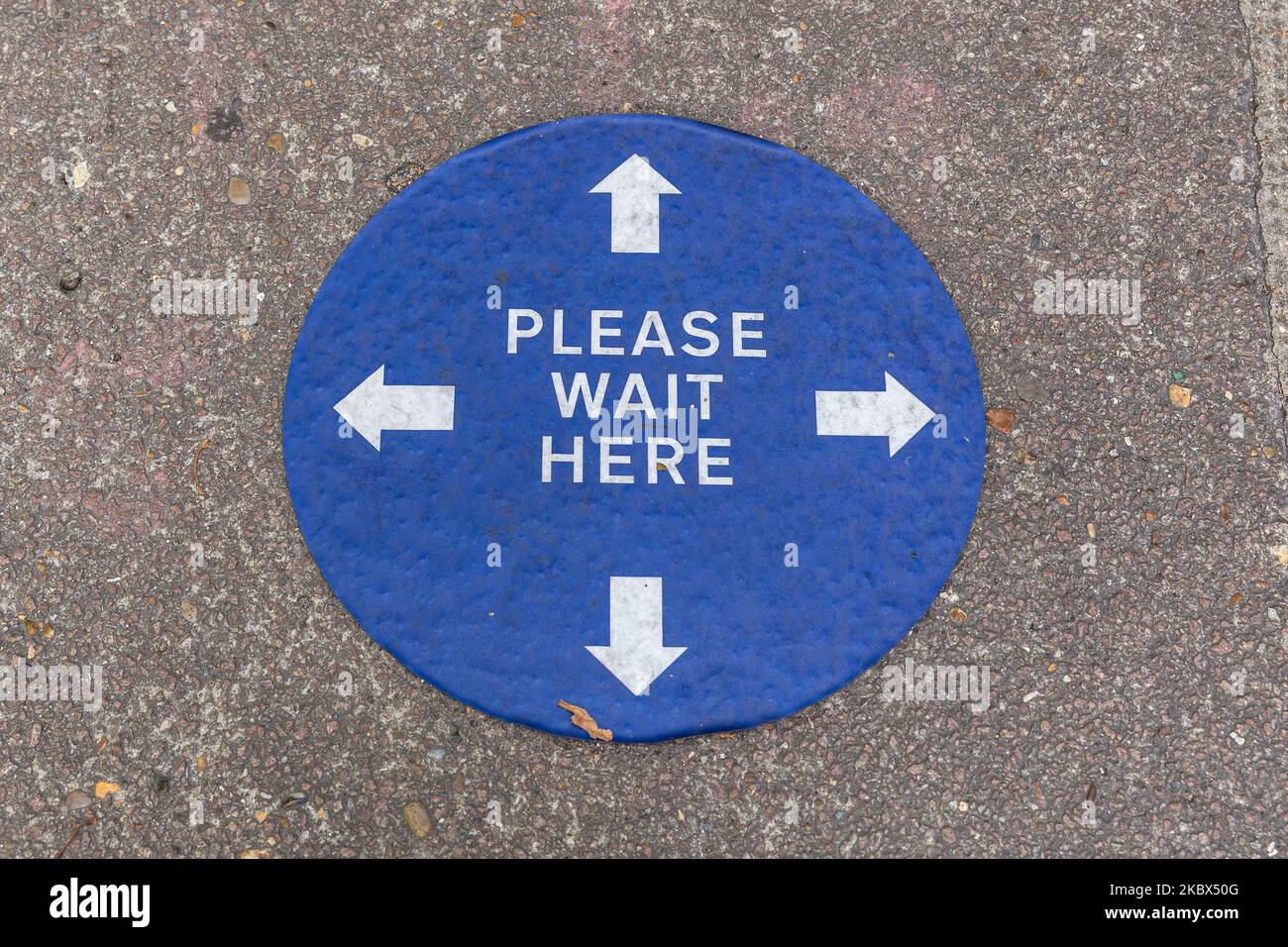 'Please wait here' pedestrian sign is seen on a pavement in London ...