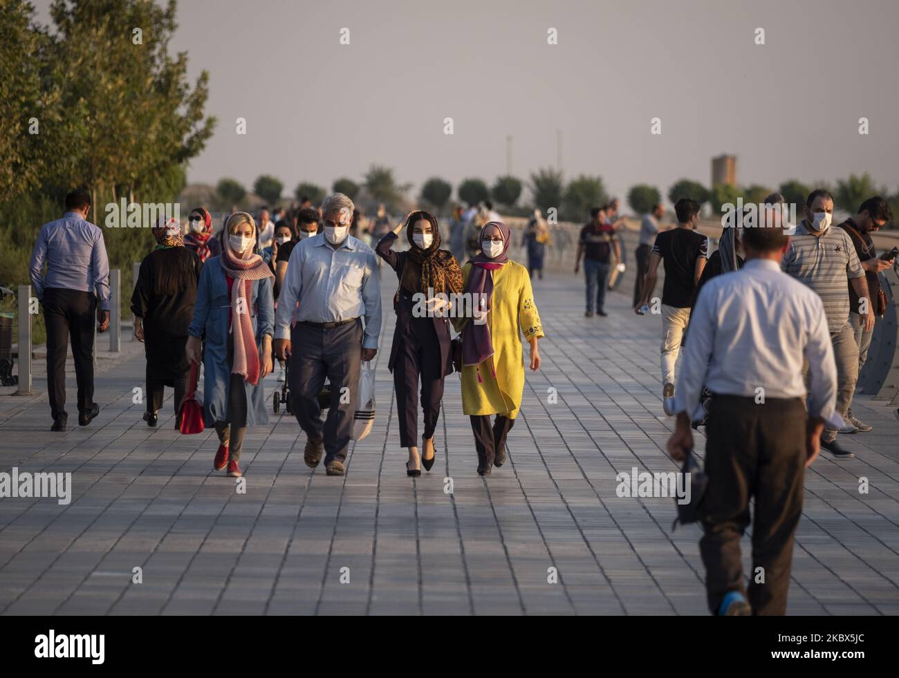 An Iranian family wearing protective face masks walk along an area in ...