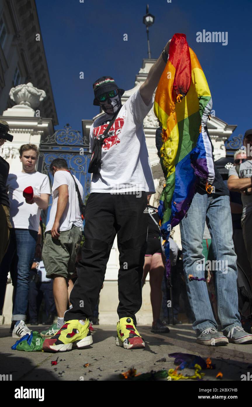 A member of a nationalist group holds a burning LGBT flag during a ...