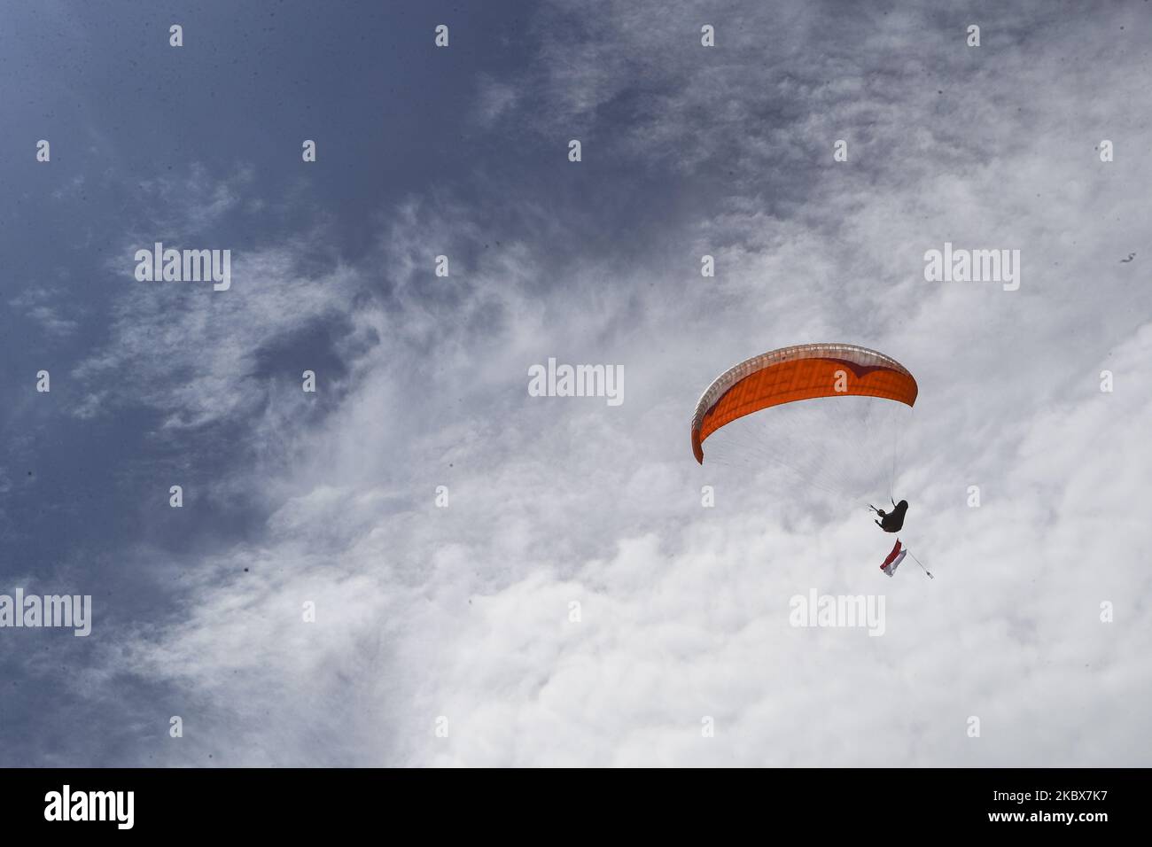 A paragliding athlete flying with the Indonesian flag. This is done to ...