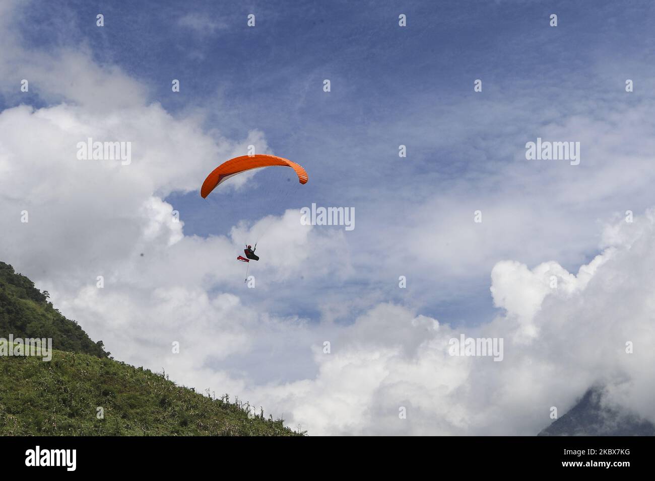 A paragliding athlete flying with the Indonesian flag. This is done to ...
