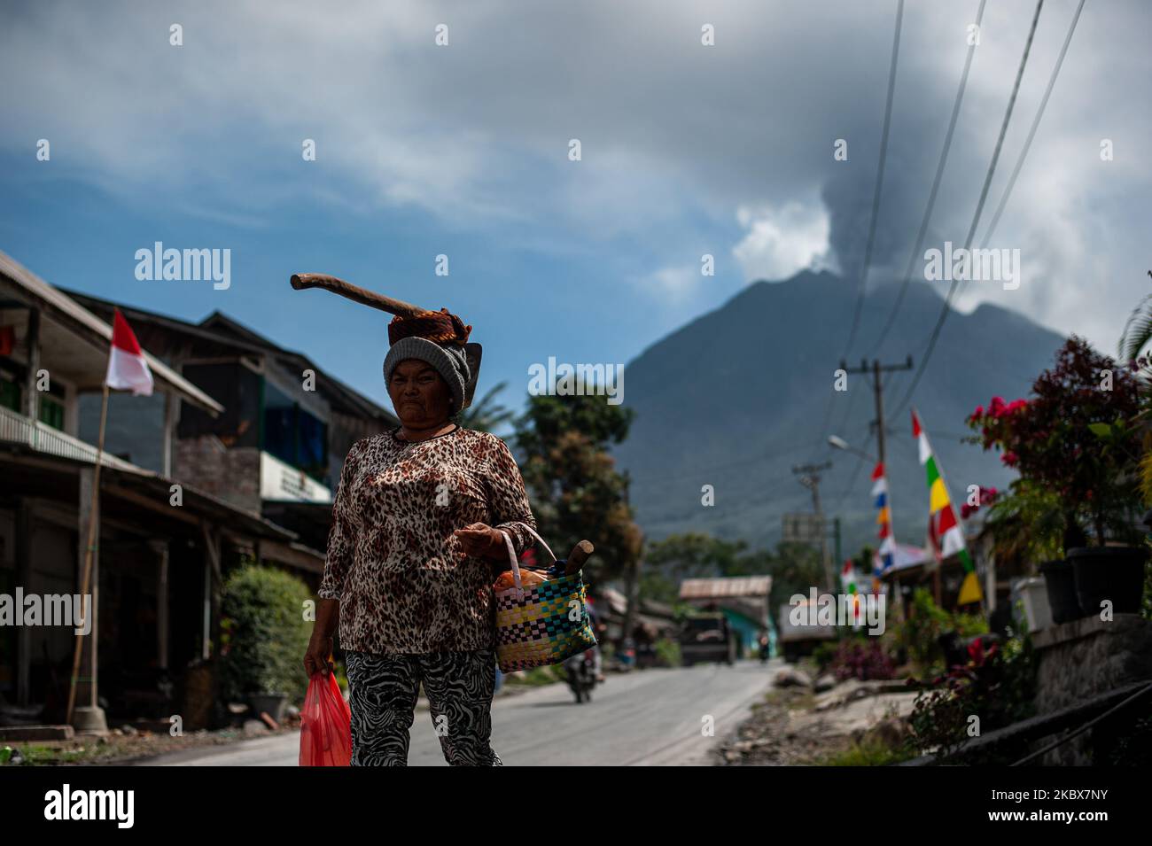 A woman farmer walks with a mask when the Sinabung volcano activity ...