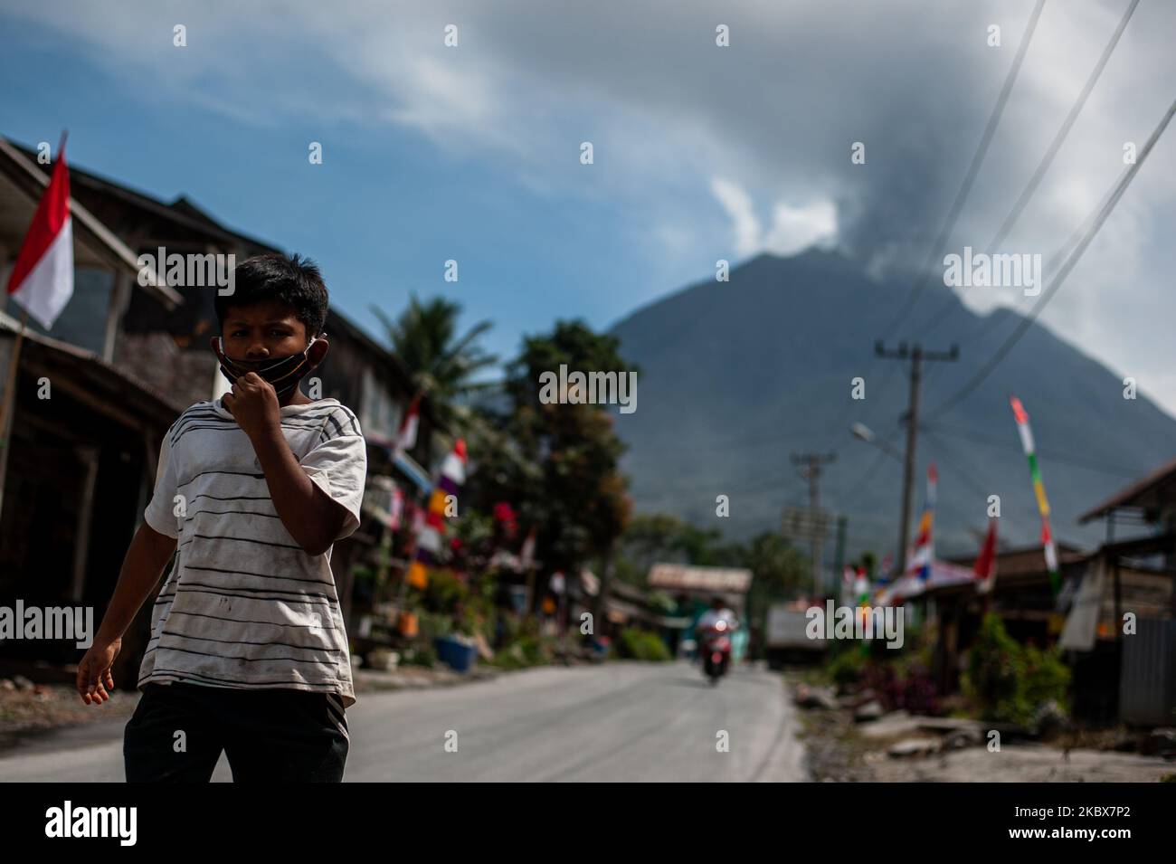 A boy walks with a mask when the Sinabung volcano activity releases ...