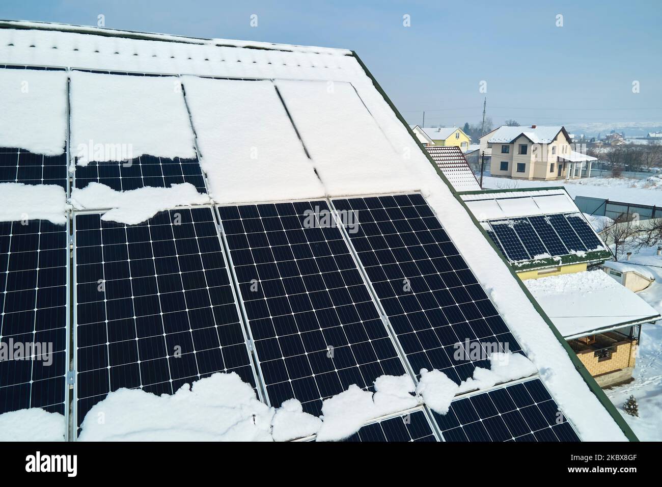 Aerial view of house roof with solar panels covered with snow melting ...
