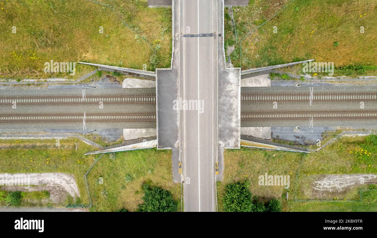 Railway in the countryside, going under a bridge, aerial view ...