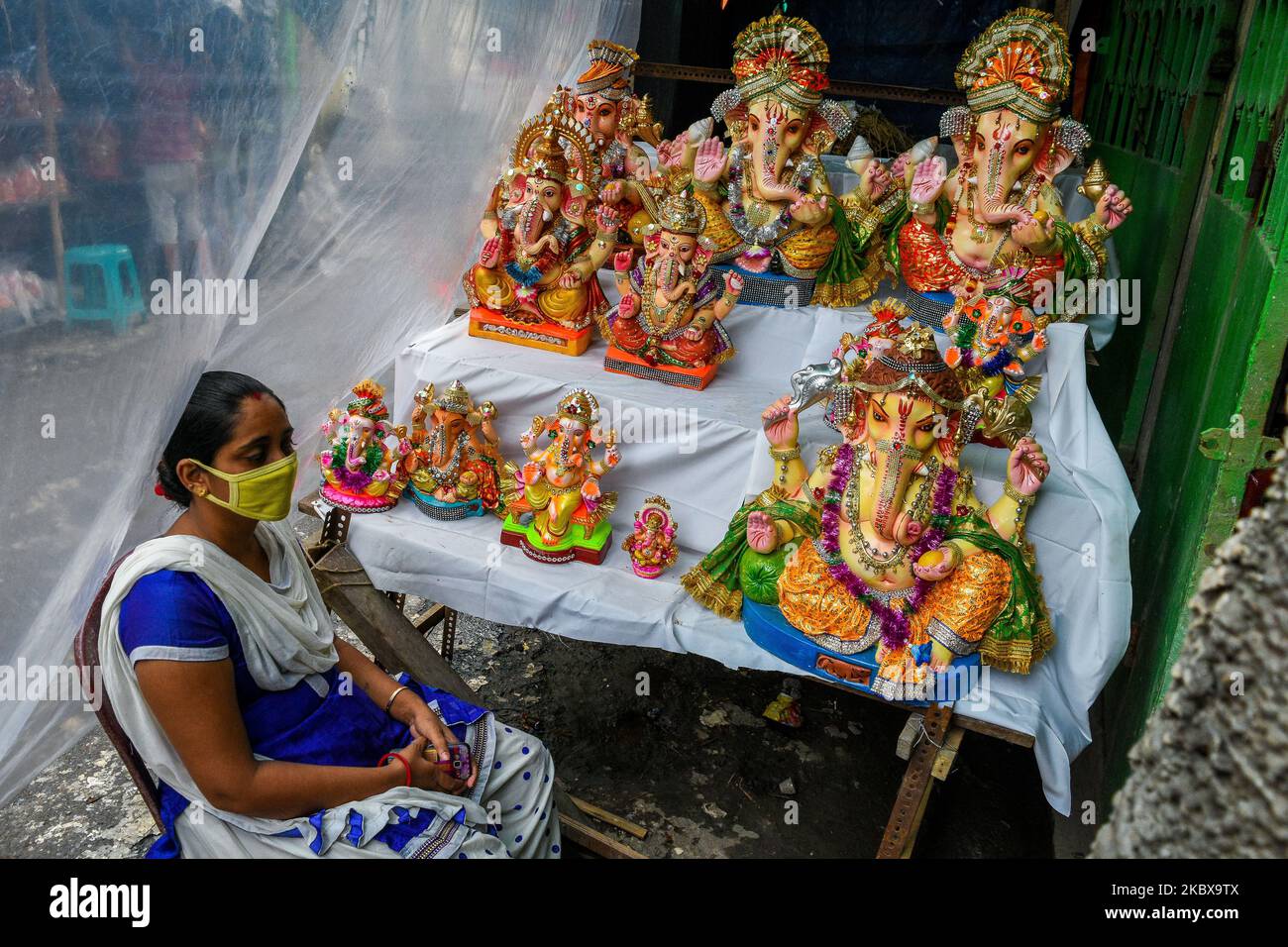 A lady wearing mask waits for customer for the Ganesha idols ahead of ...
