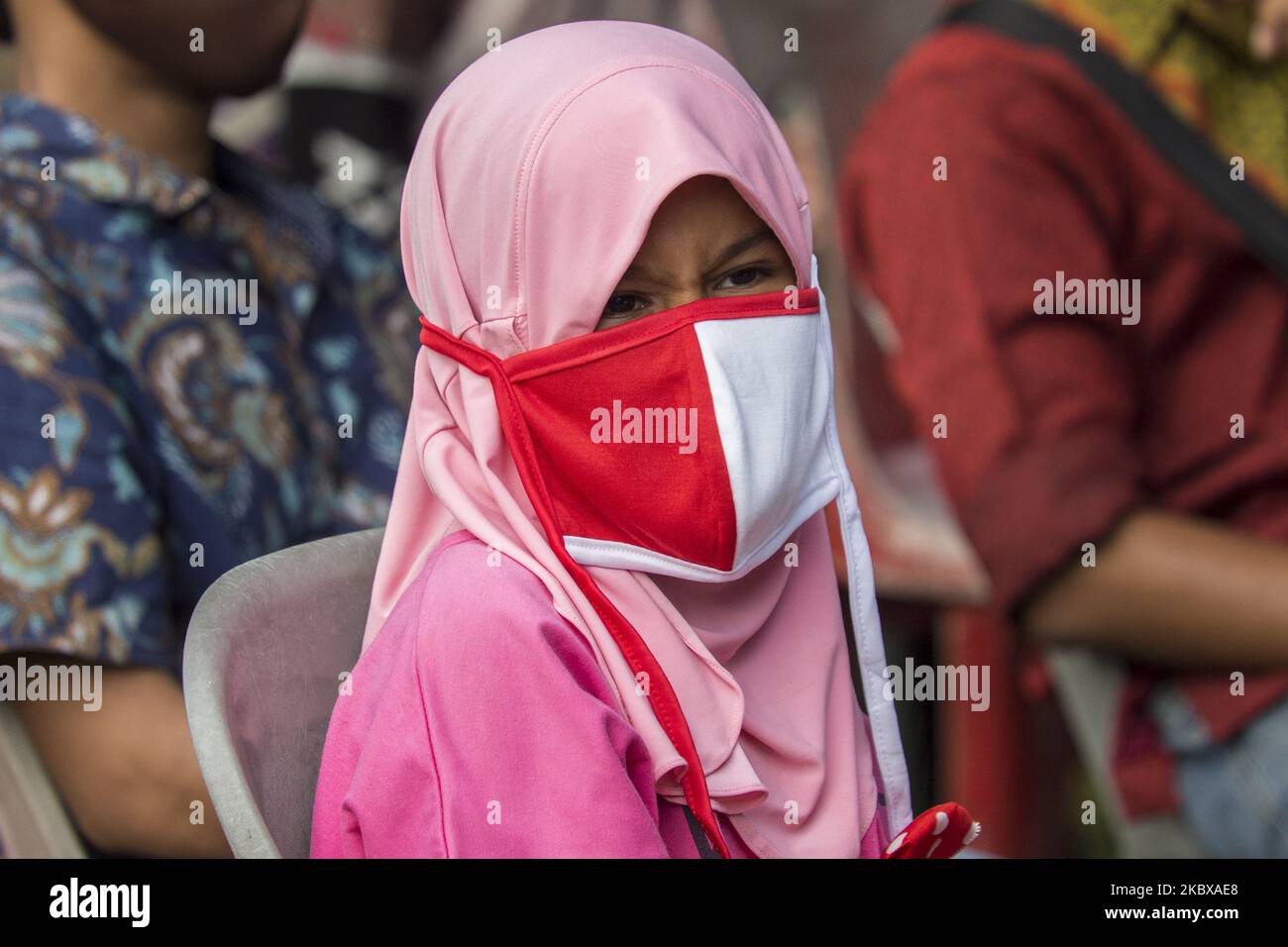 Residents wear red and white masks with the symbol of the Indonesian ...
