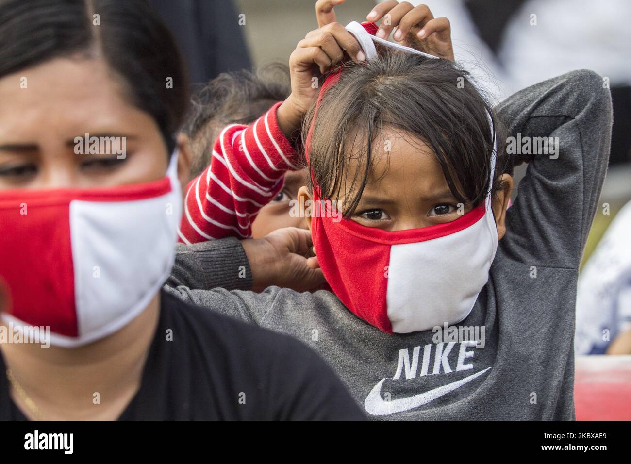 Residents wear red and white masks with the symbol of the Indonesian ...