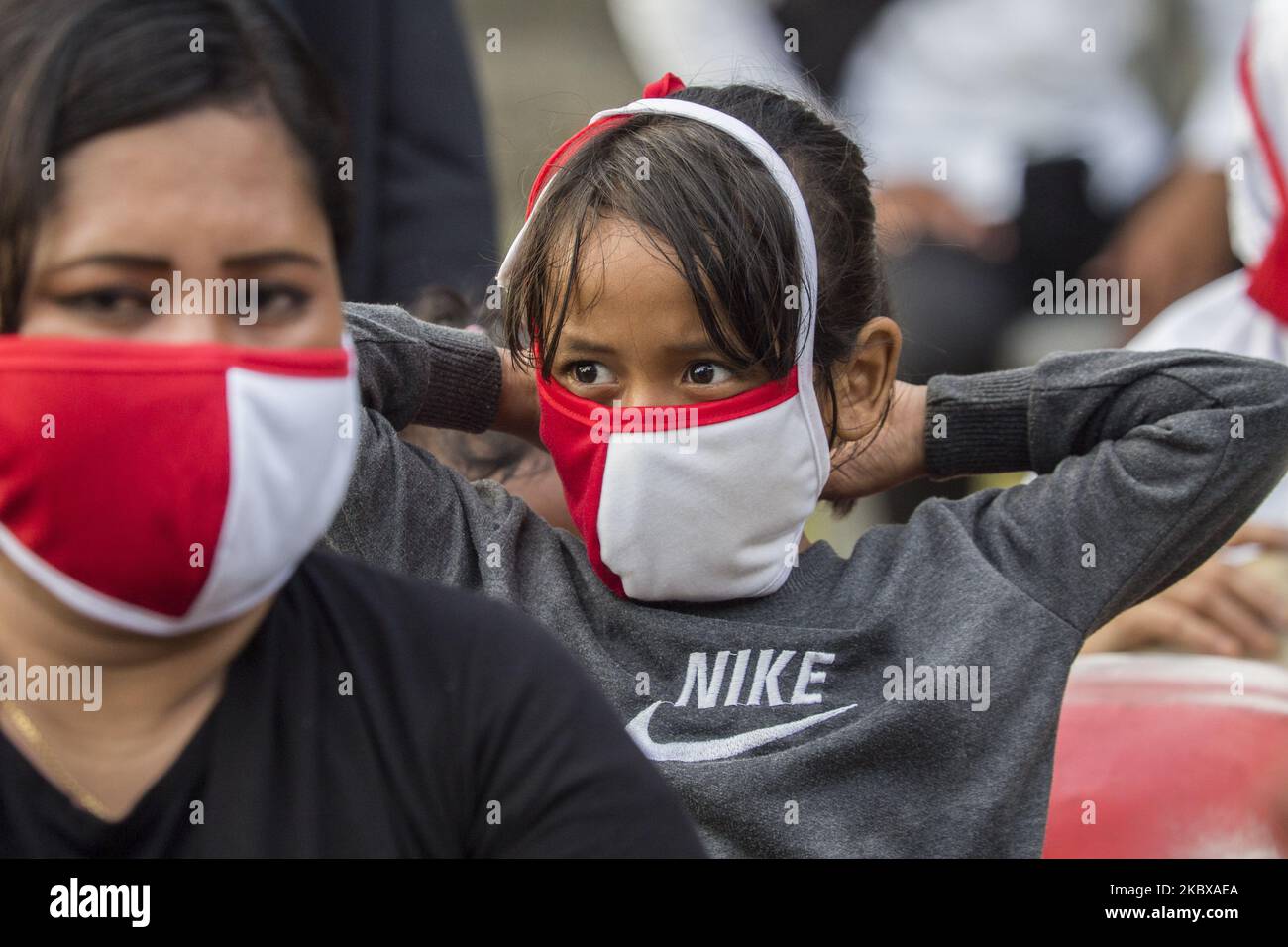 Residents wear red and white masks with the symbol of the Indonesian ...