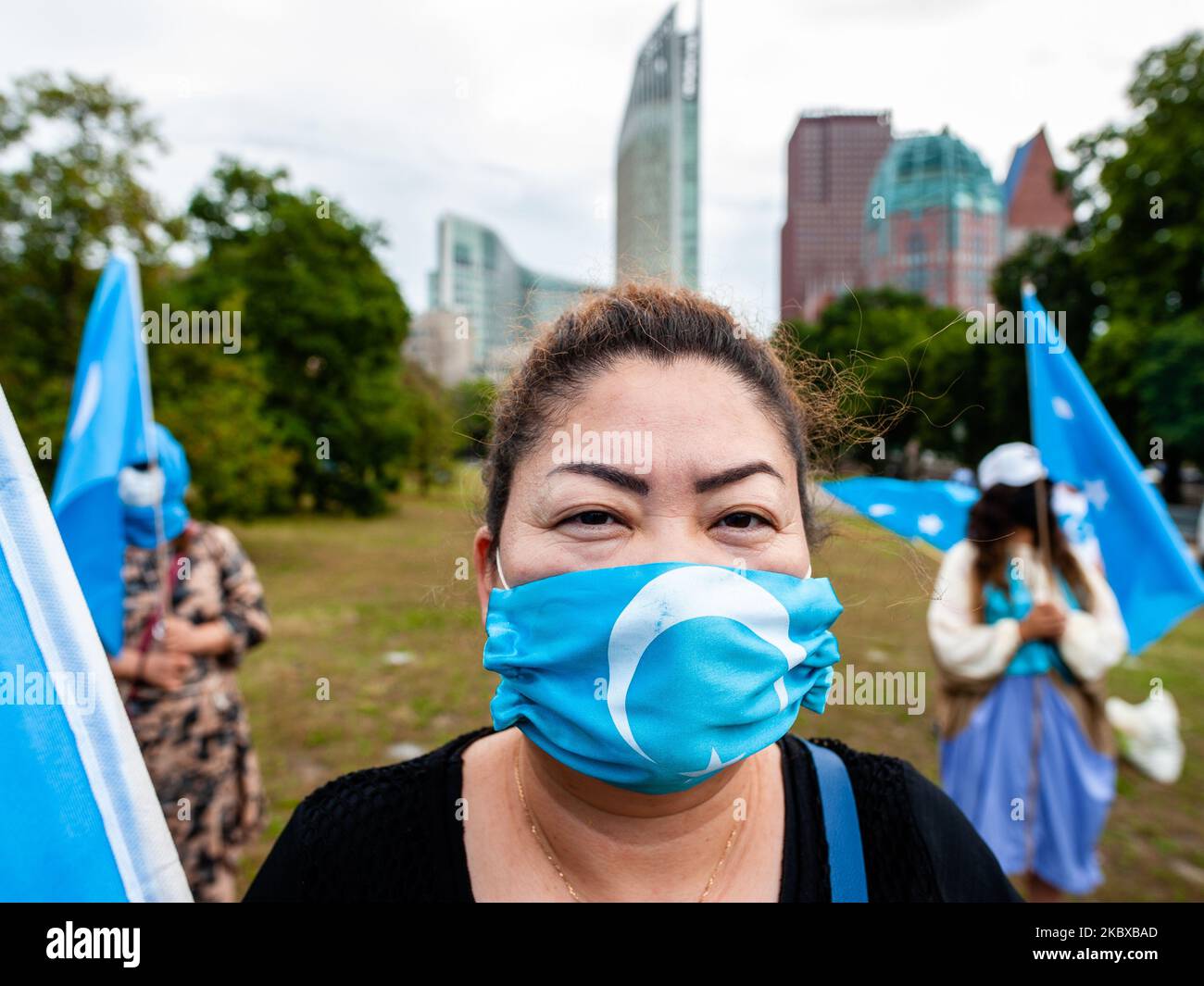 A woman is wearing a mask with the Uyghurs flag on it, during the ...
