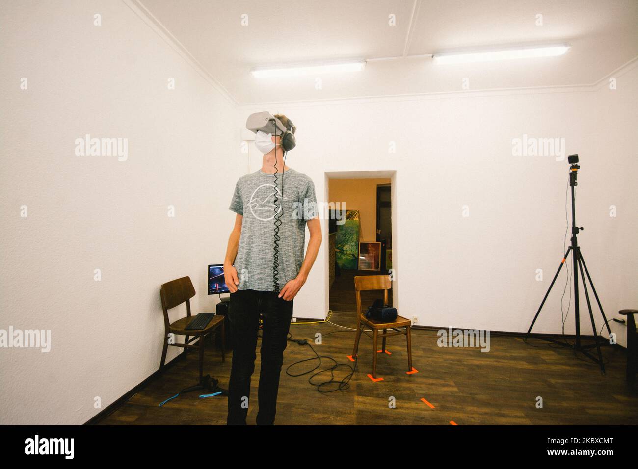 a visitor with a face mask experiences VR in a small studio at places ...