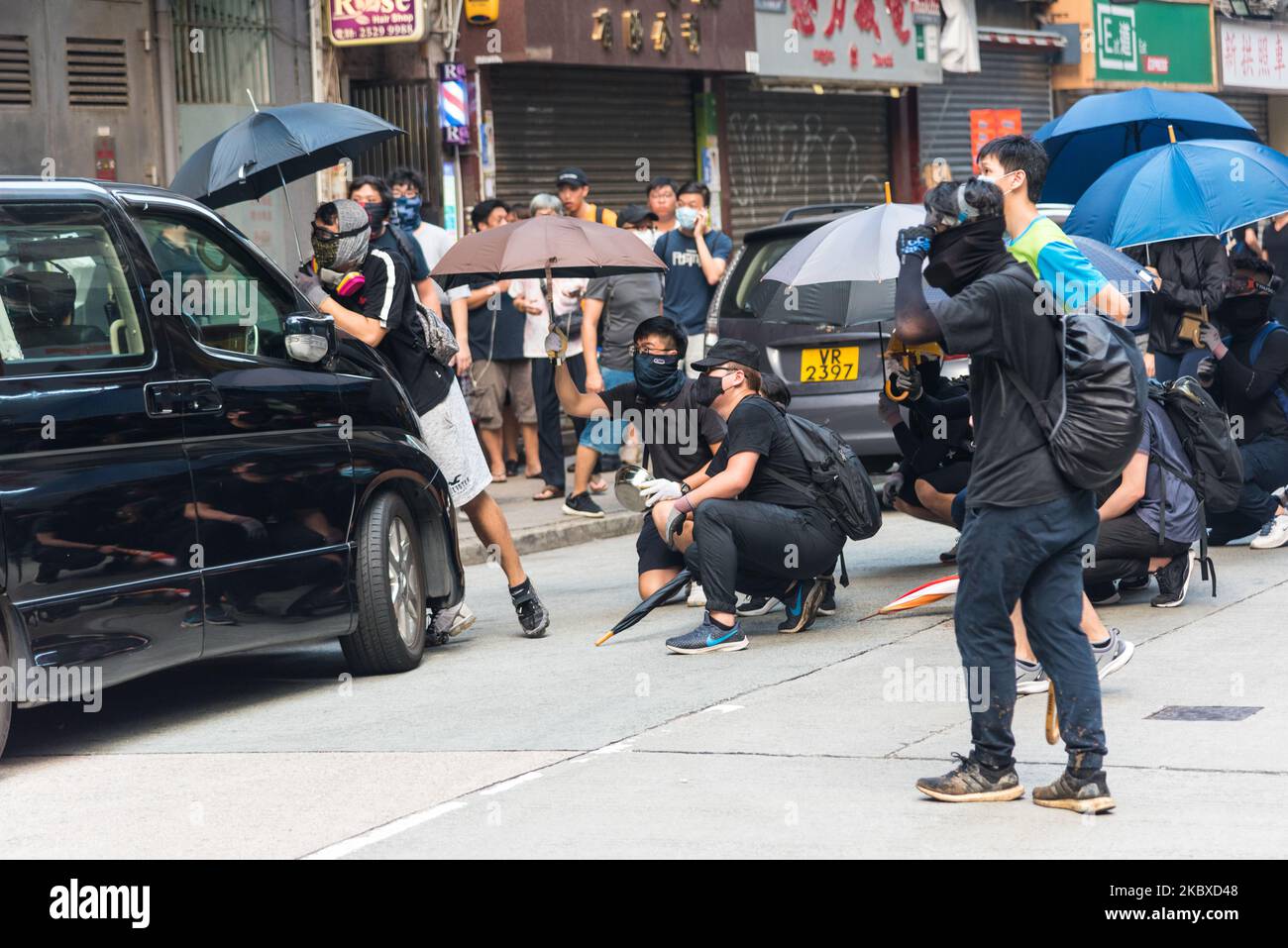 Protesters take cover behind cars while getting ready to extinguish ...